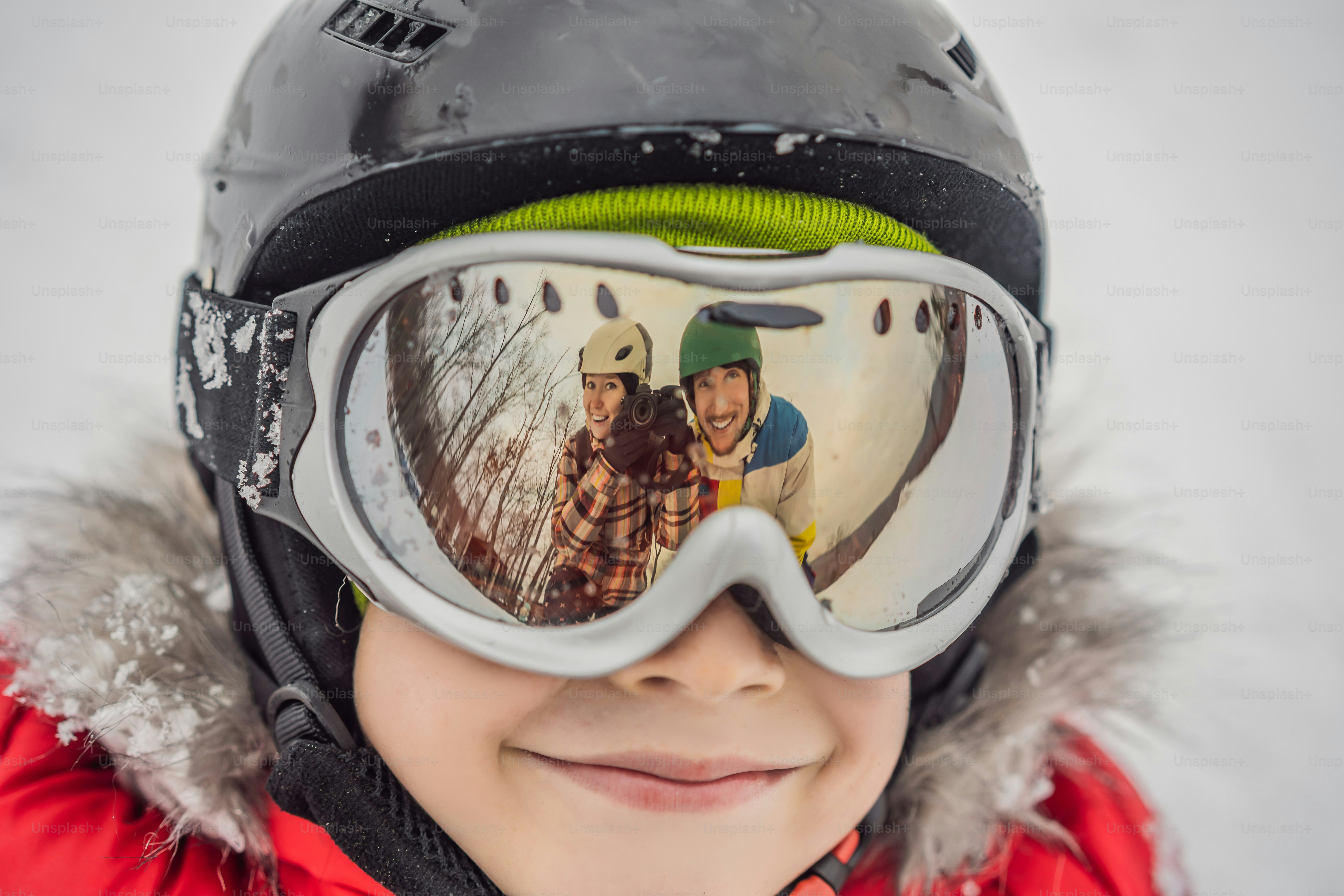 Mom and Dad are reflected in the boy ski goggles. Mom and Dad teach a ...