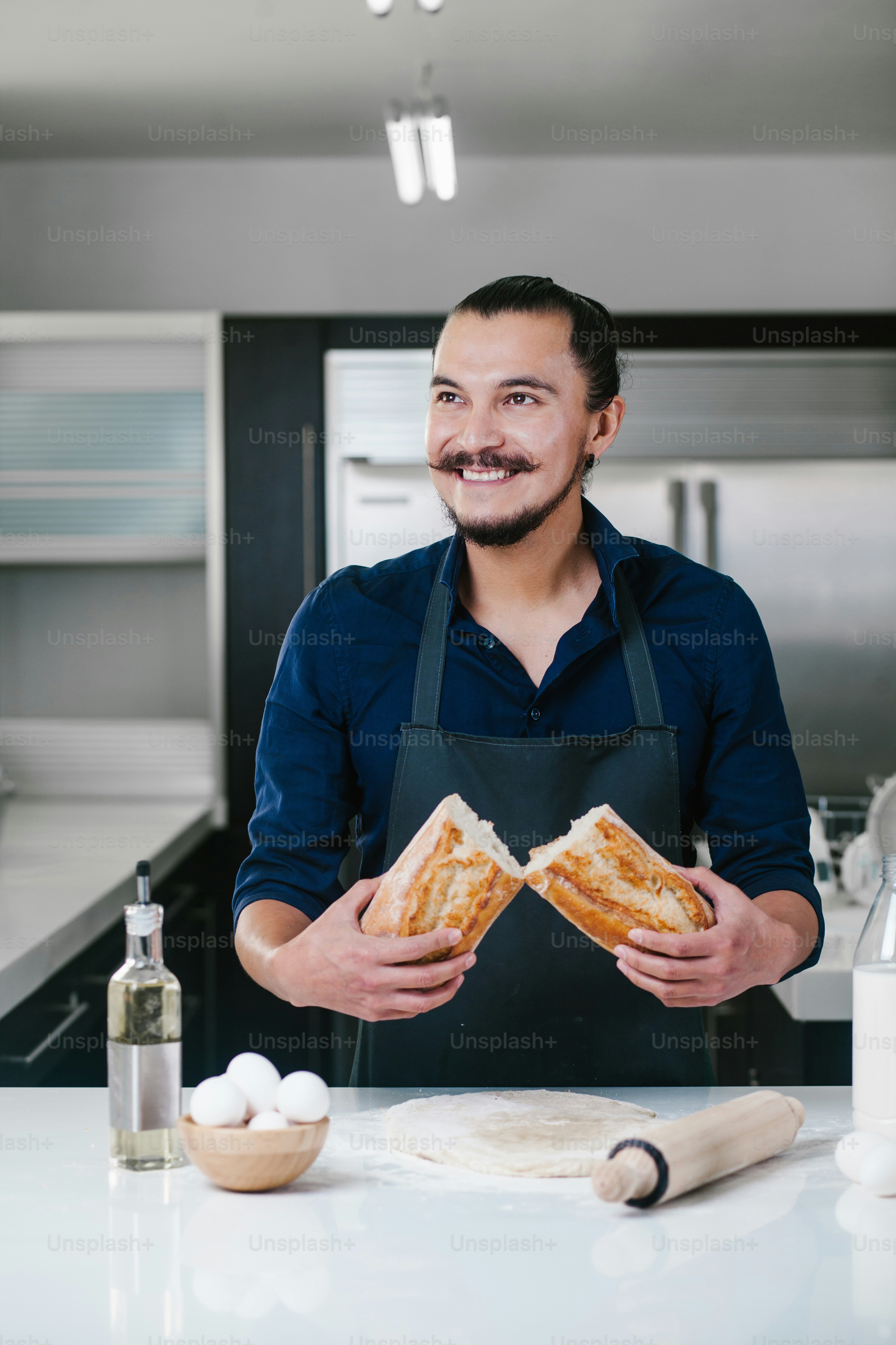 Portrait of Latin man baking and holding bread at kitchen in Mexico ...