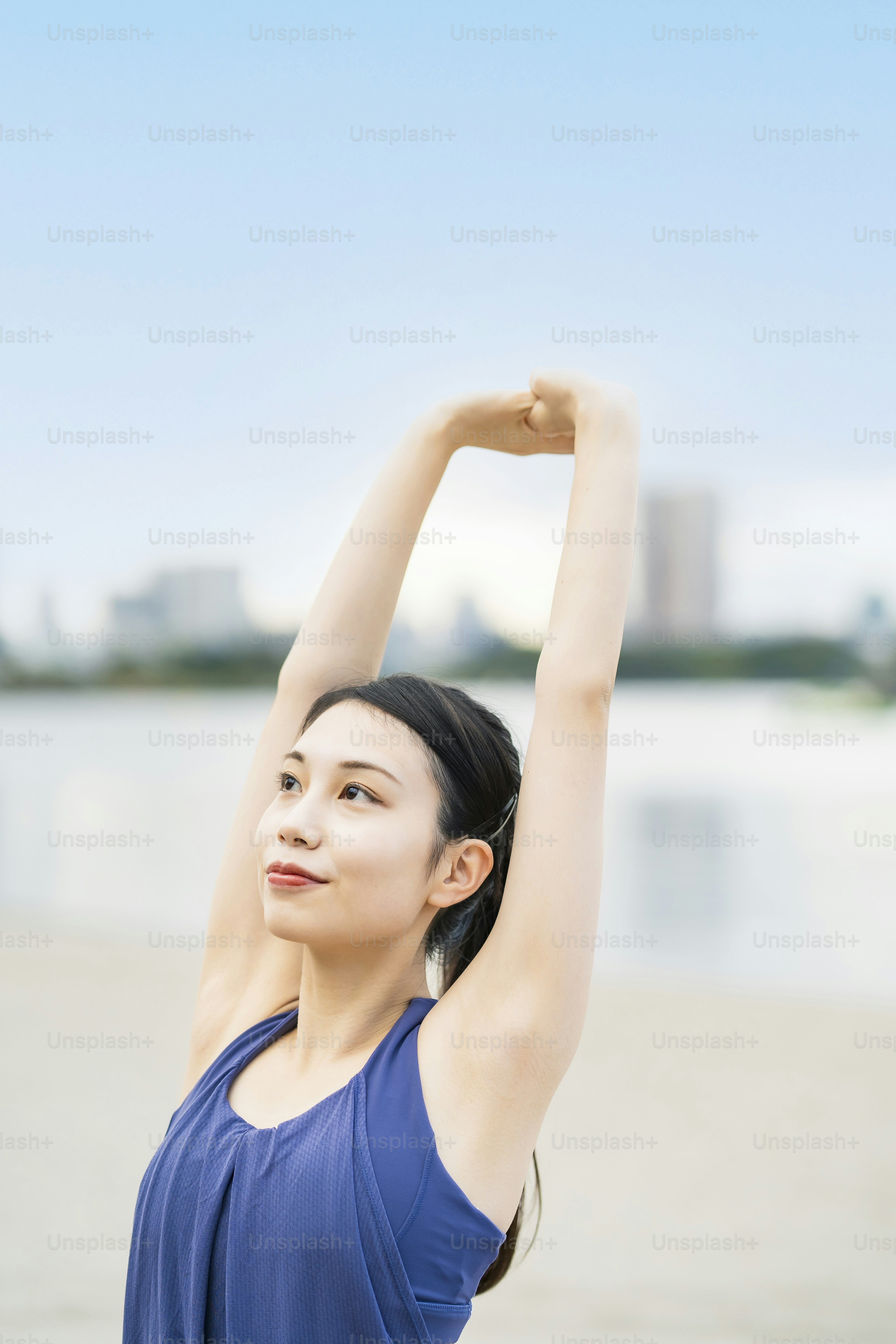 Young woman stretching and taking a deep breath on the beach of the ...