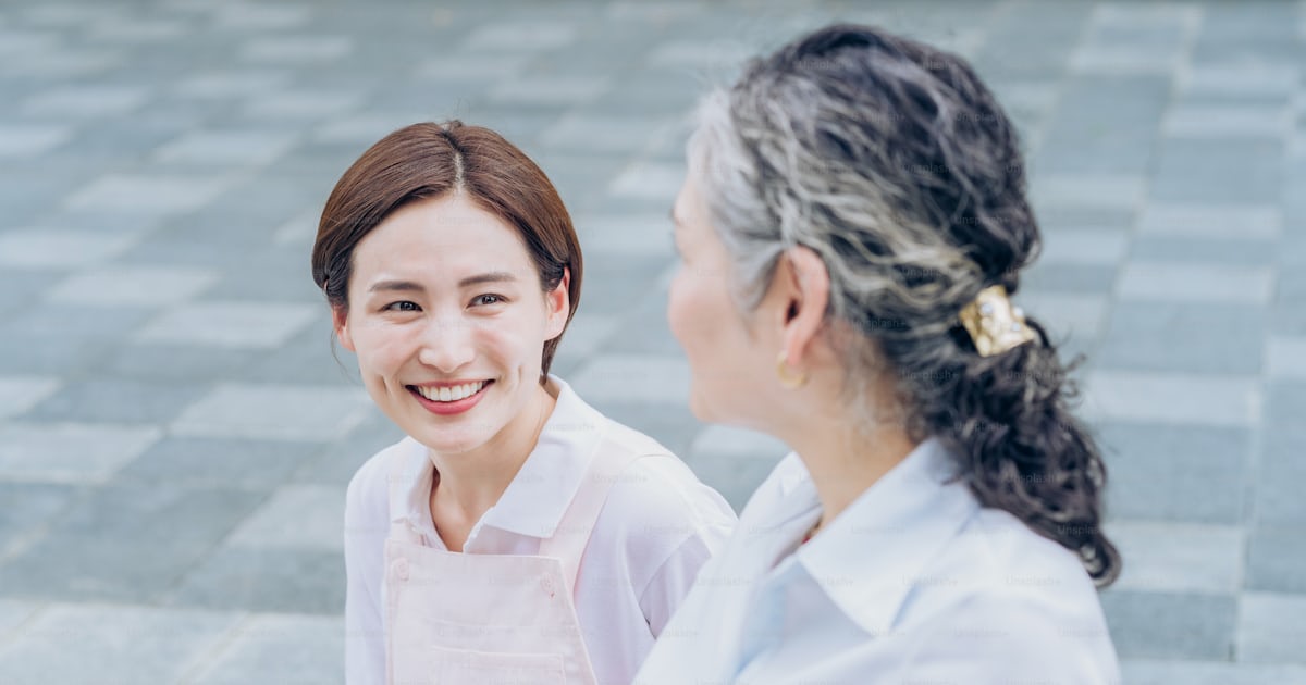 앞치마를 두른 여자가 야외에서 노인 여성과 이야기하고 있다 사진 Unsplash의 사람 이미지