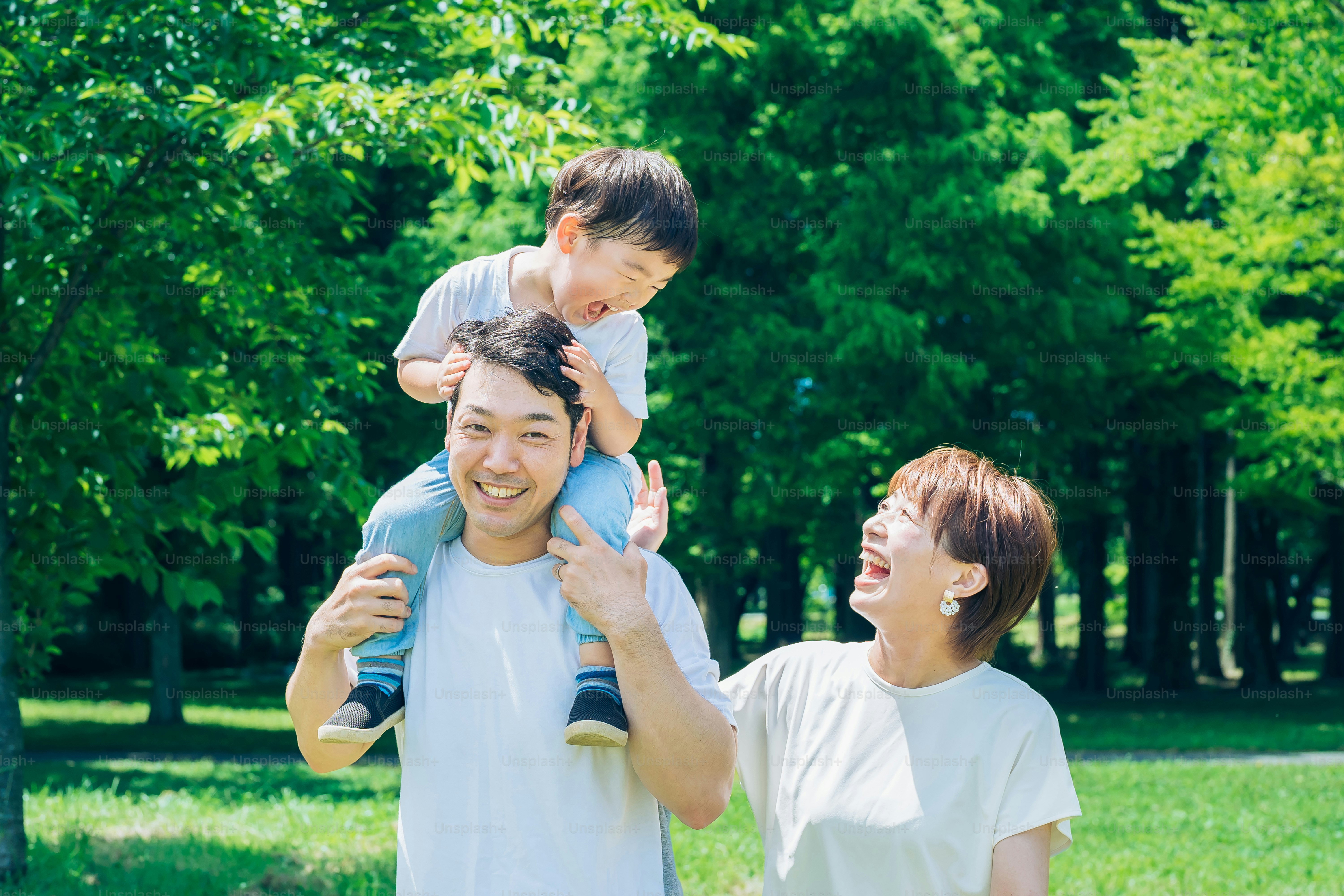 Parents and child playing happily while piggybacking in the park photo ...
