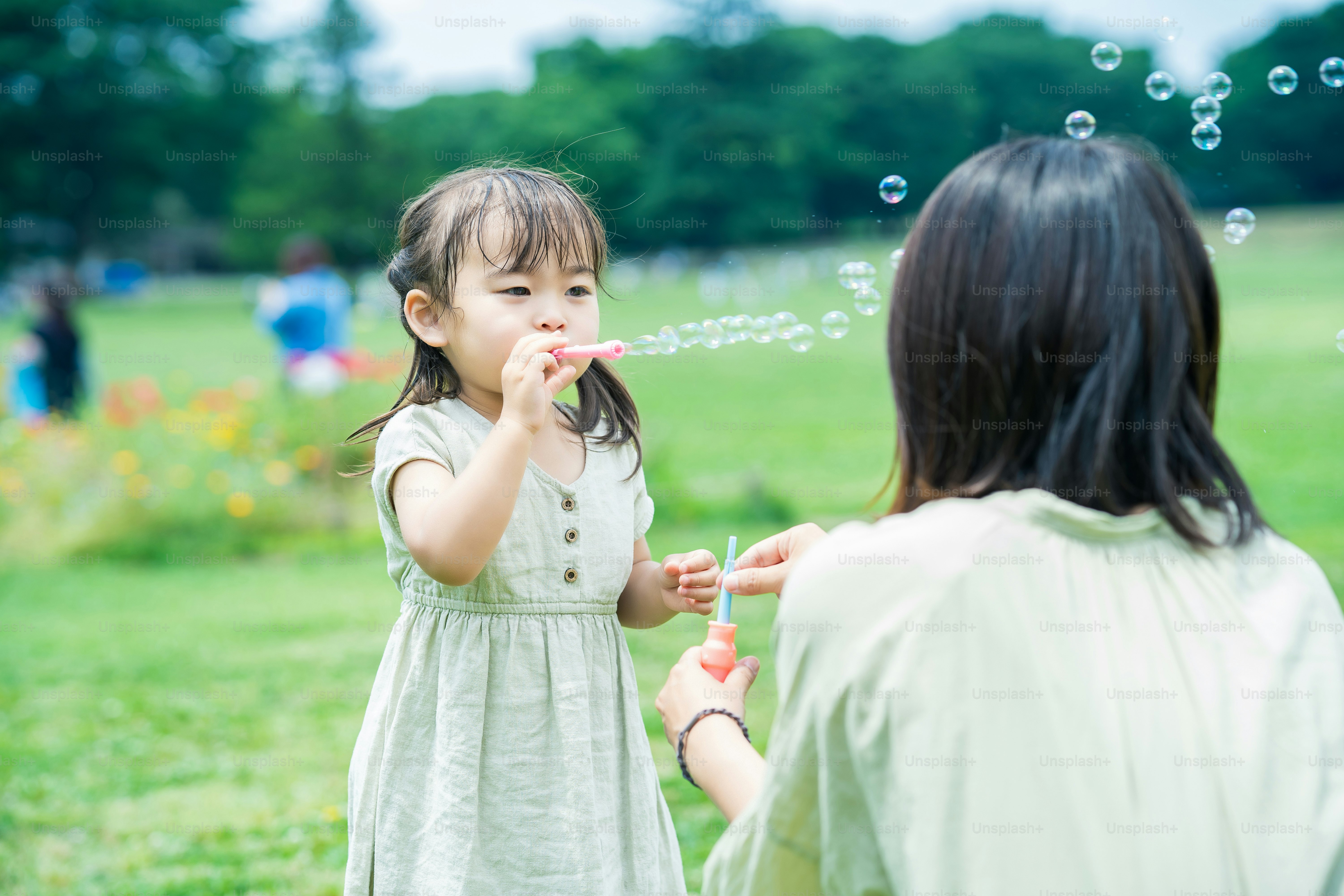Une mère et sa fille jouent avec des bulles de savon dans le parc photo ...