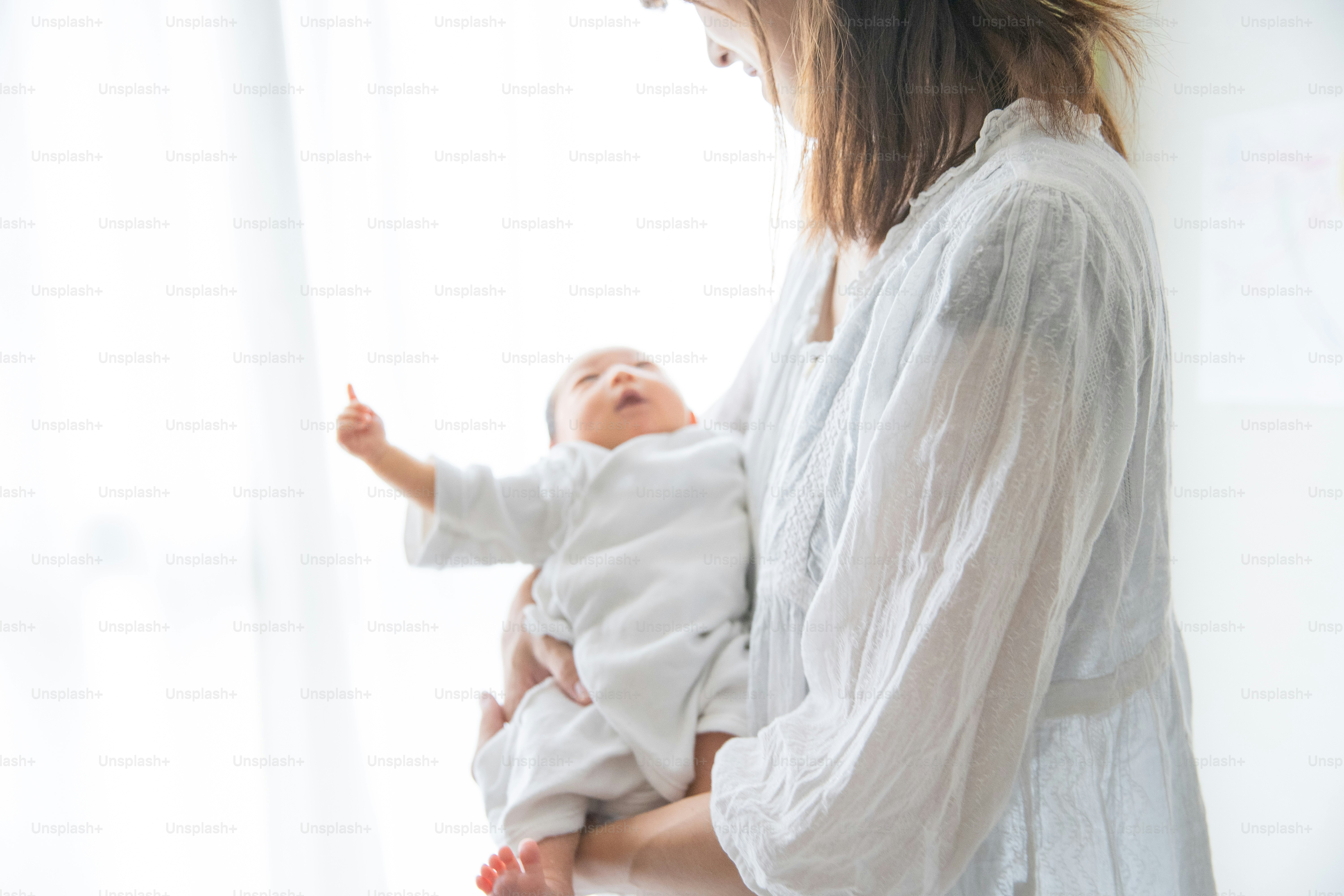 A mother carrying an Asian (Japanese) newborn baby (0 year old 0 month ...