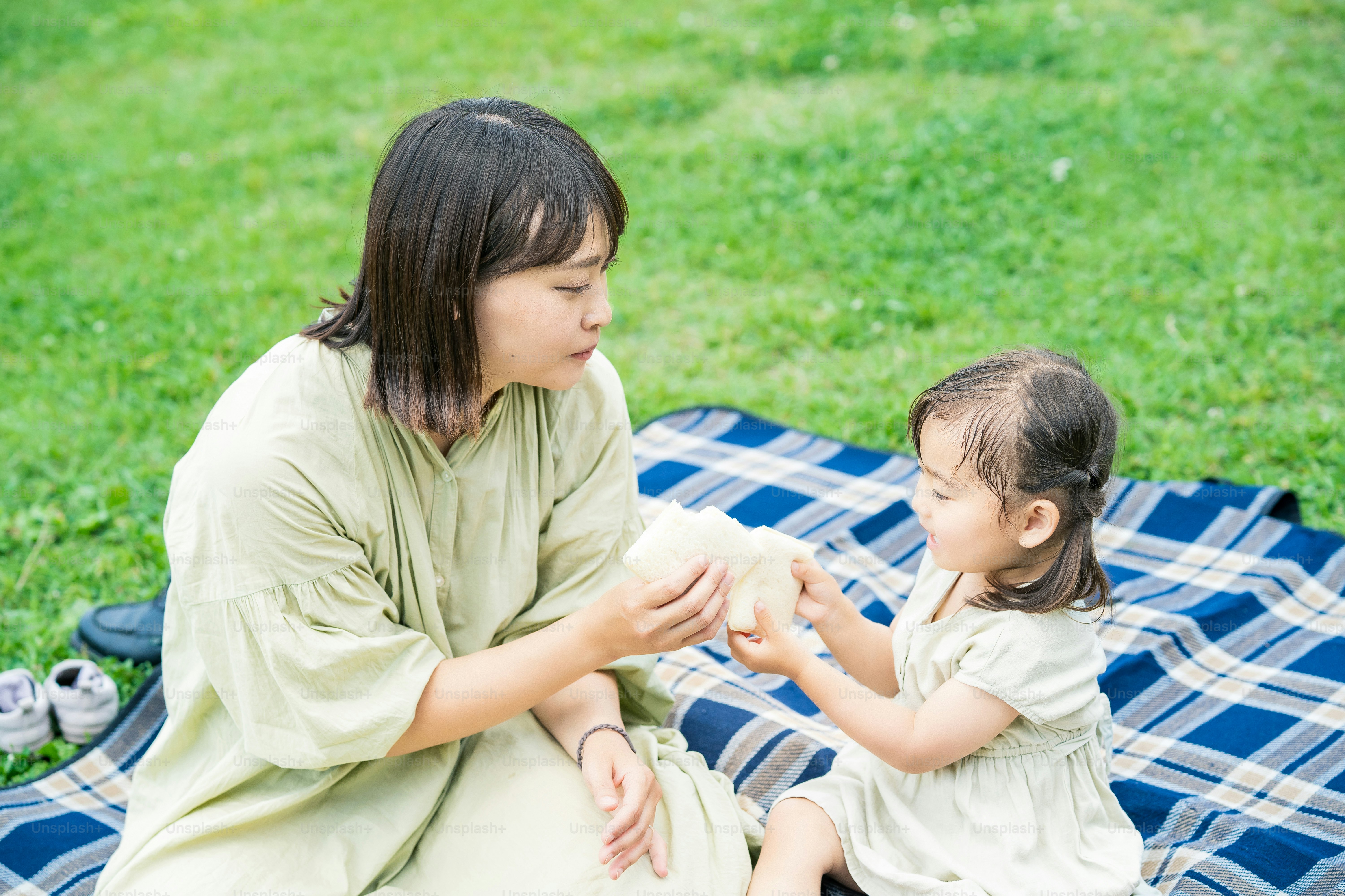 Foto Madre y su hija comiendo sándwiches en el parque en un buen día ...