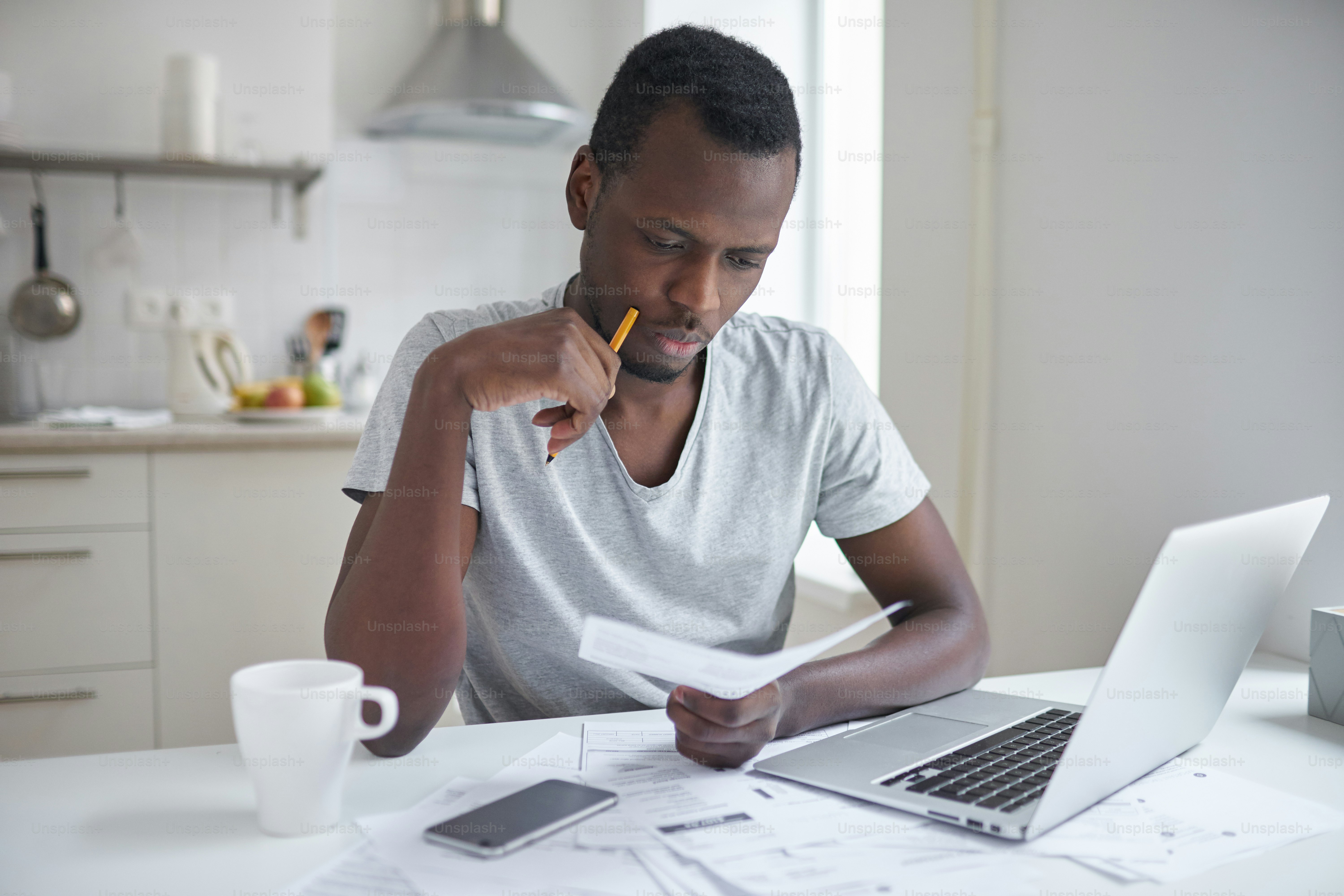 Stressed african american man working through paperwork, calculating ...