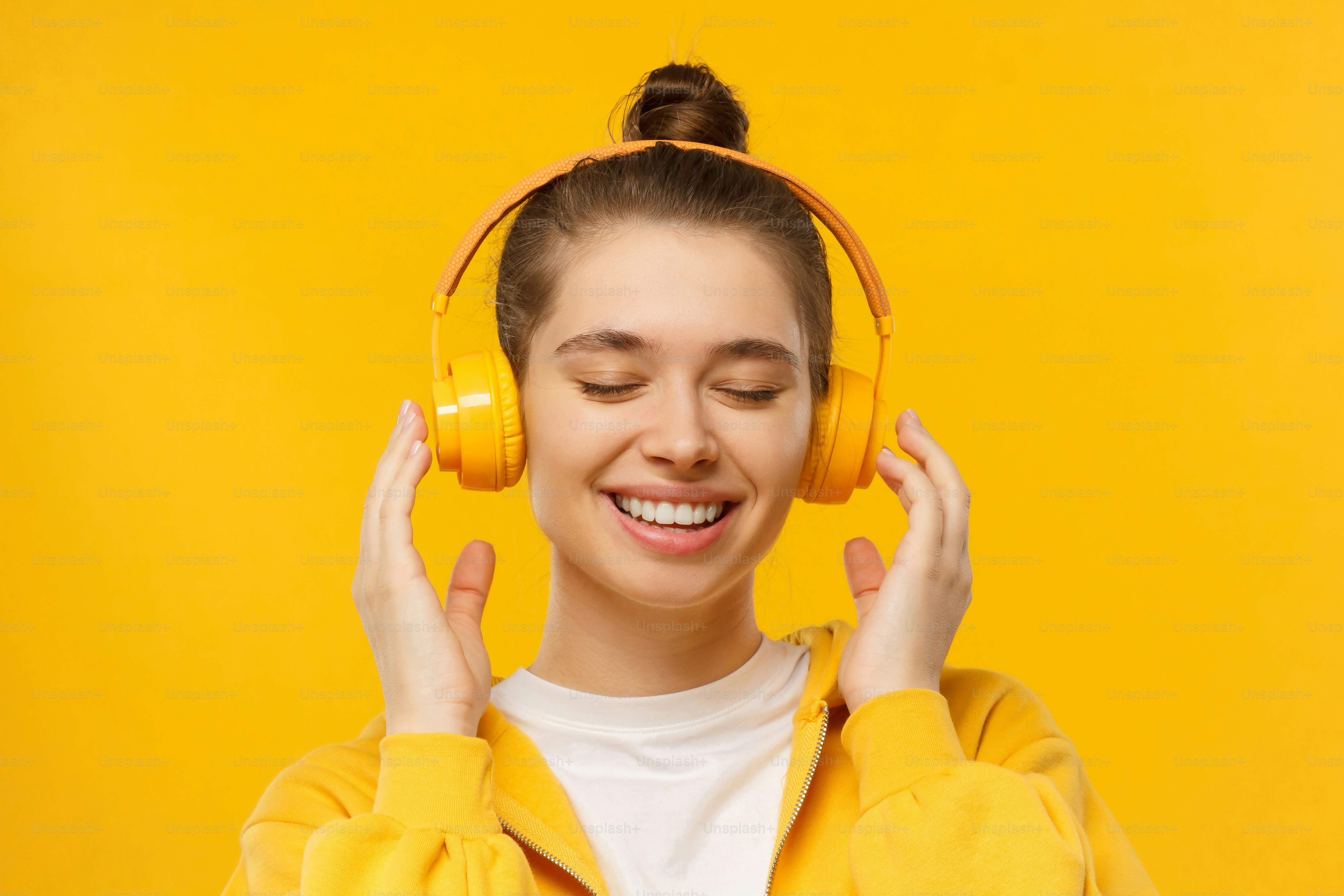 Young girl listening to music via wireless headphones with eyes closed ...