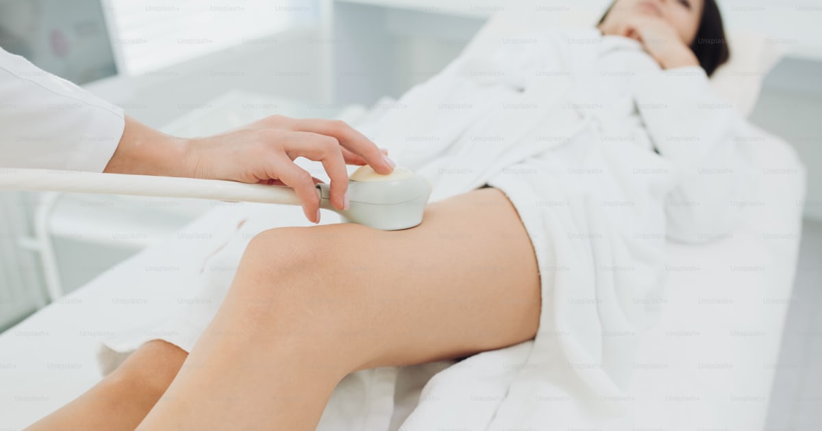 미용실에서 여성의 길고 가느다란 다리에 Rf 리프팅 시술을 하는 알아볼 수 없는 여성 미용사 과체중 및 연약한 피부 치료