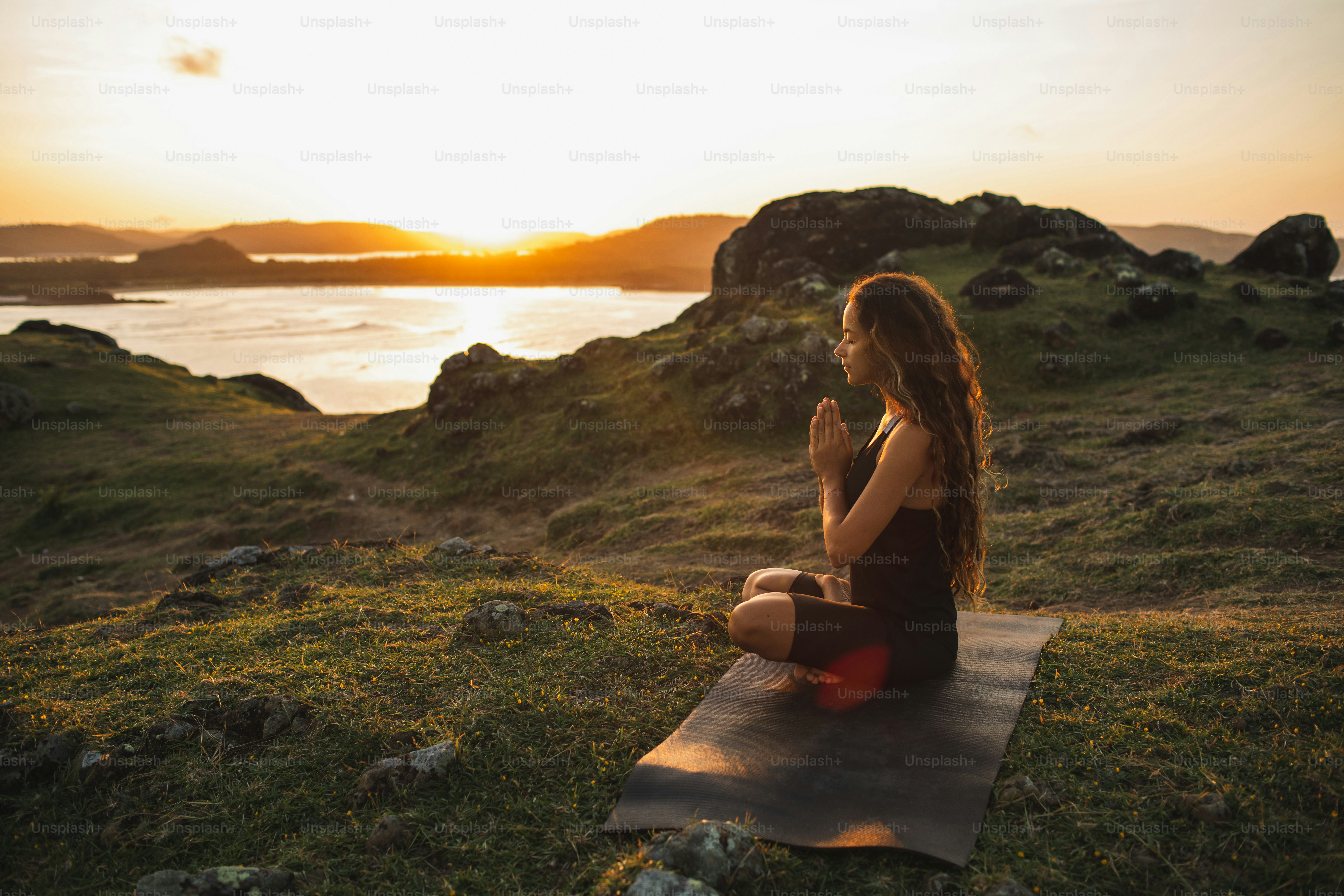 Young woman practicing yoga poses at sunset with beautiful ocean and ...