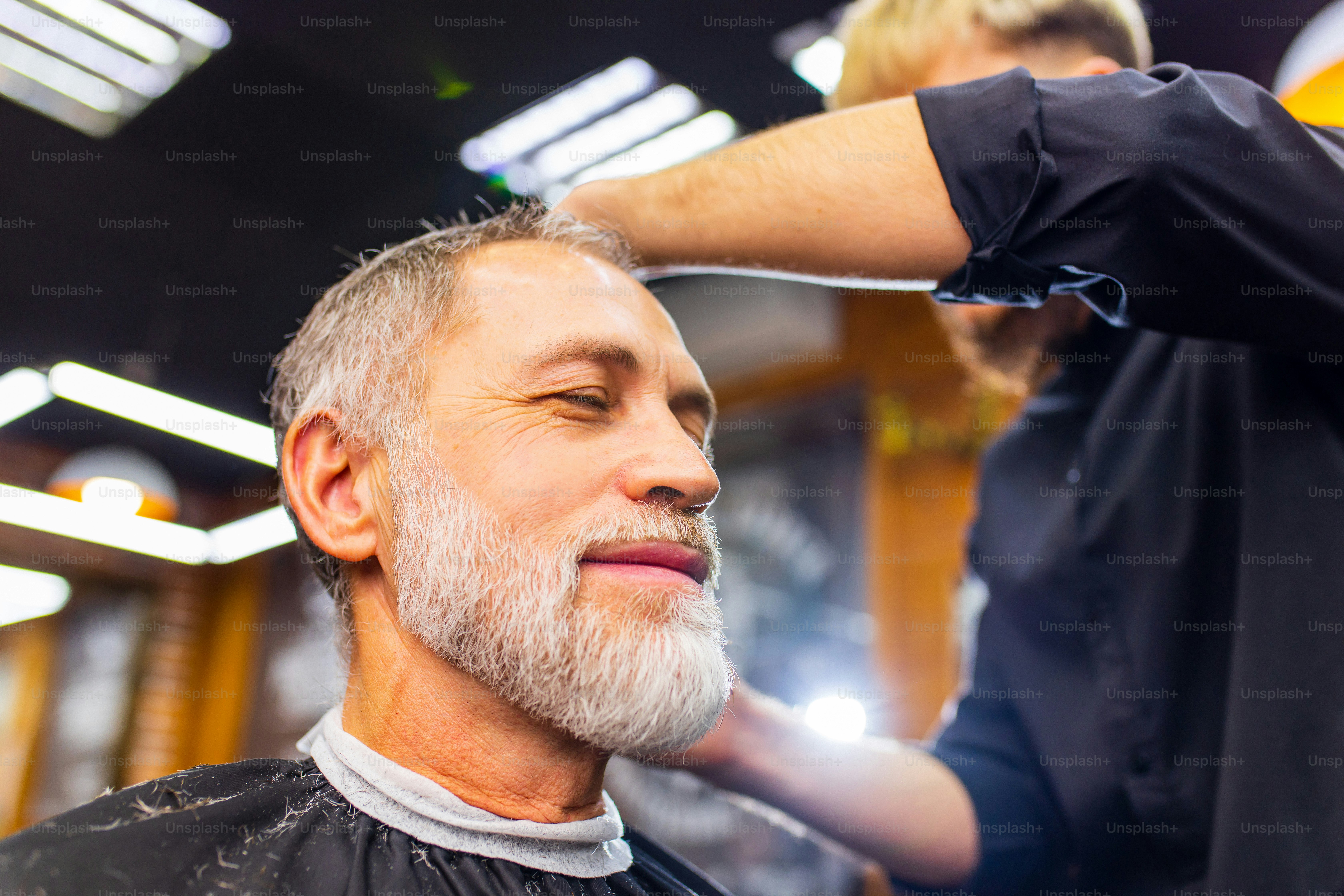 Retired man visiting barbershop , sitting in the barber's chair while ...
