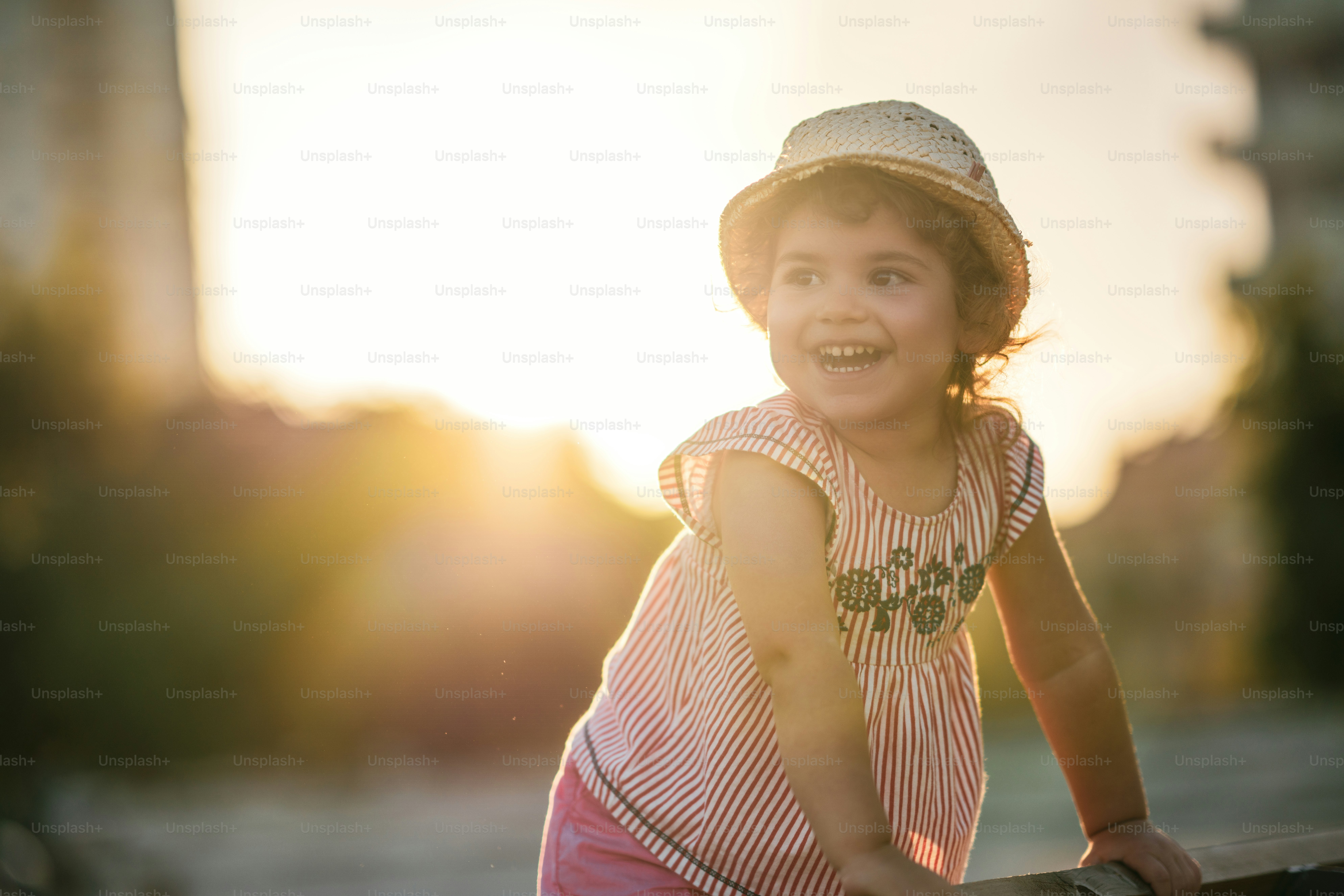 Portrait of a cute beautiful and happy girl standing on bench in the ...