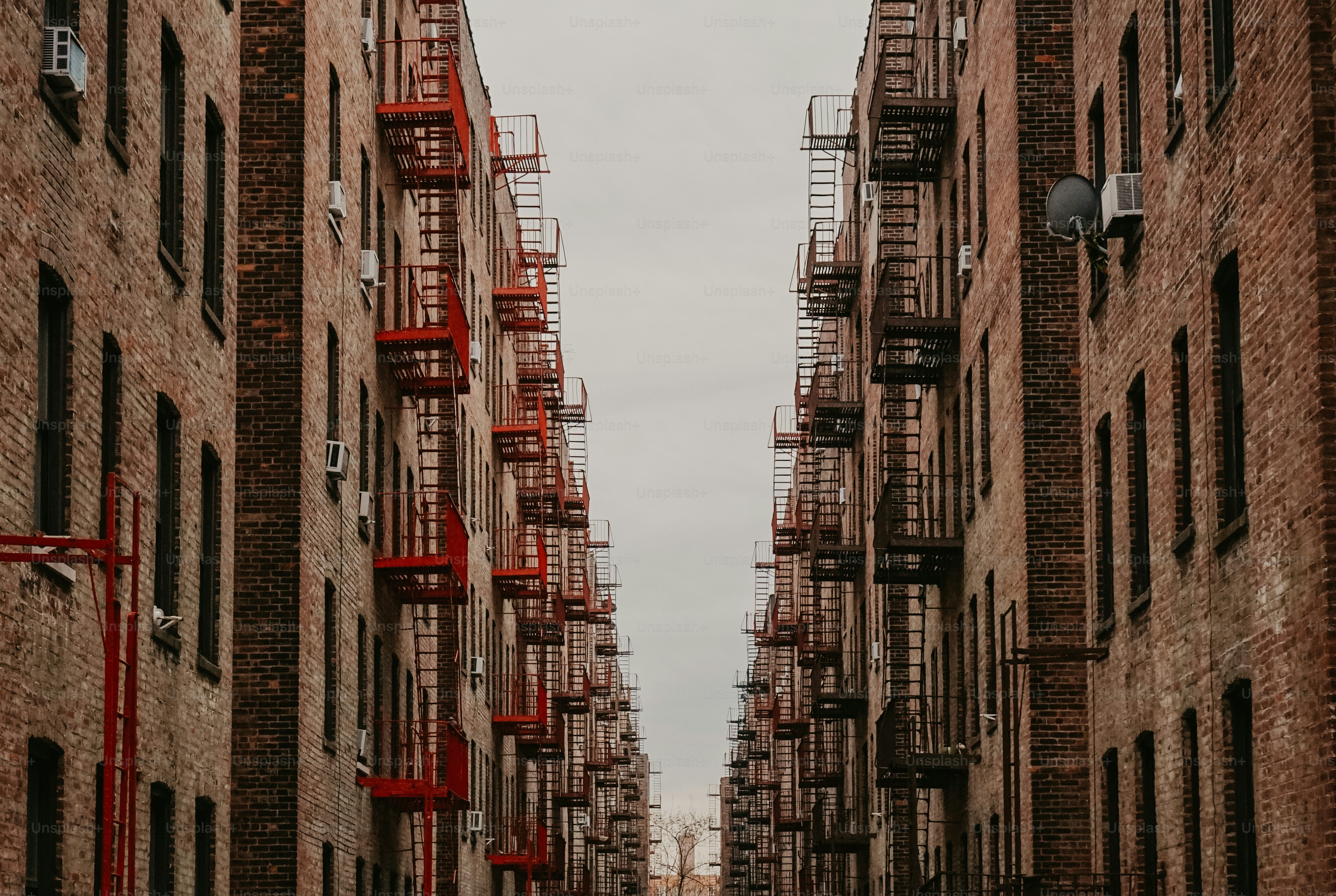 A couple of people walking down a street next to tall buildings photo ...