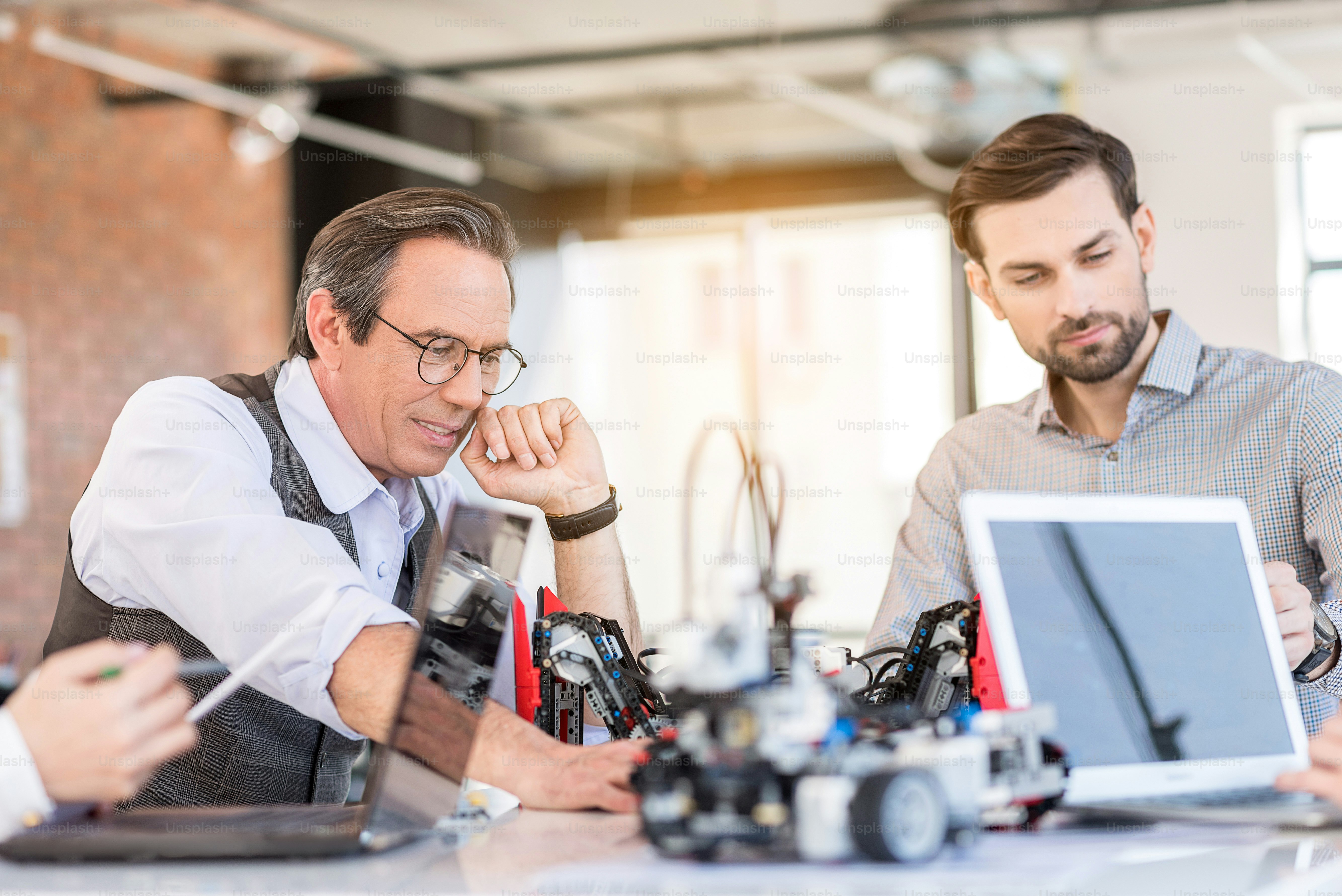 Our tech project. Attentive concentrated workers sitting at table and ...