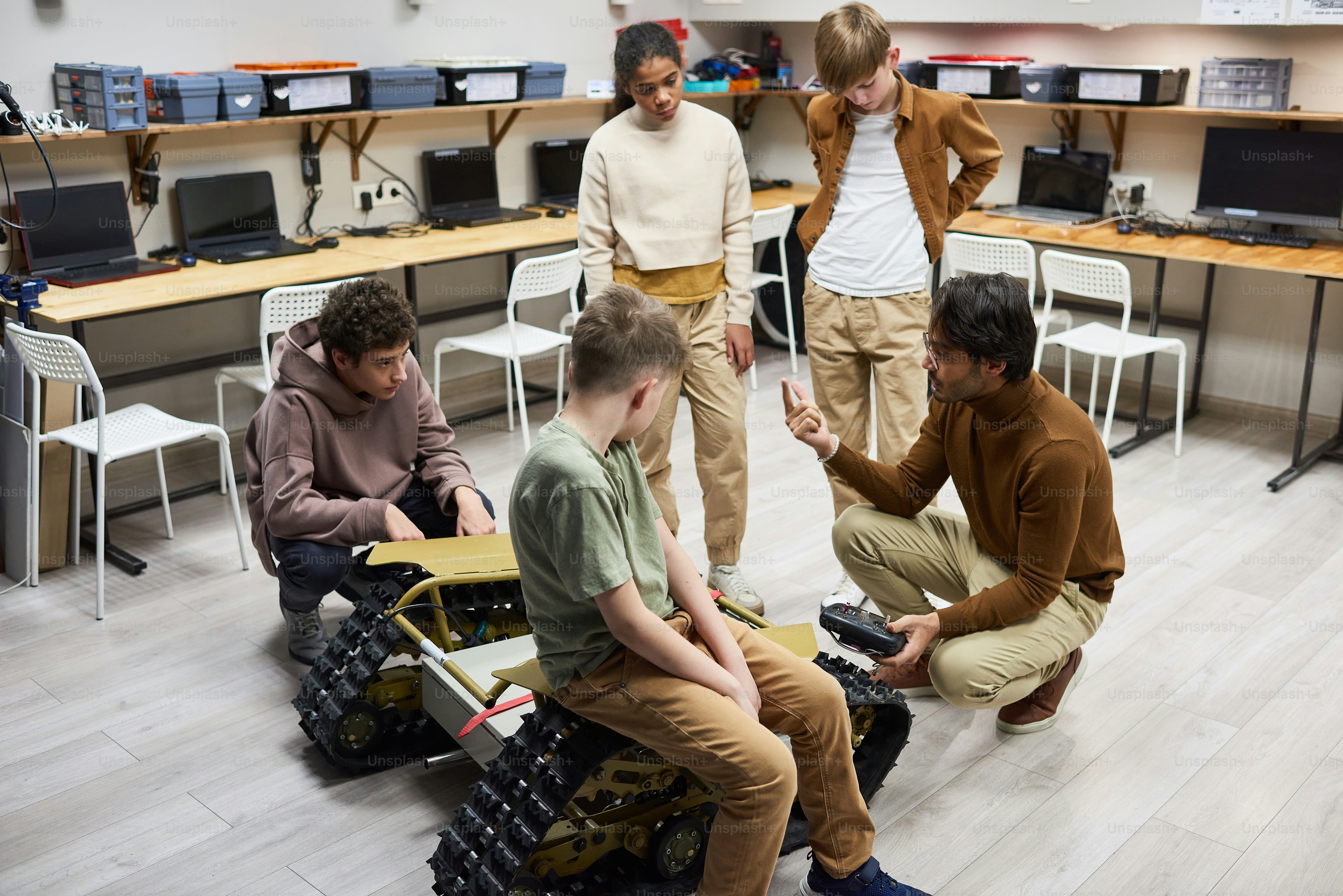 Young teacher showing his students how to build robotic machine while ...