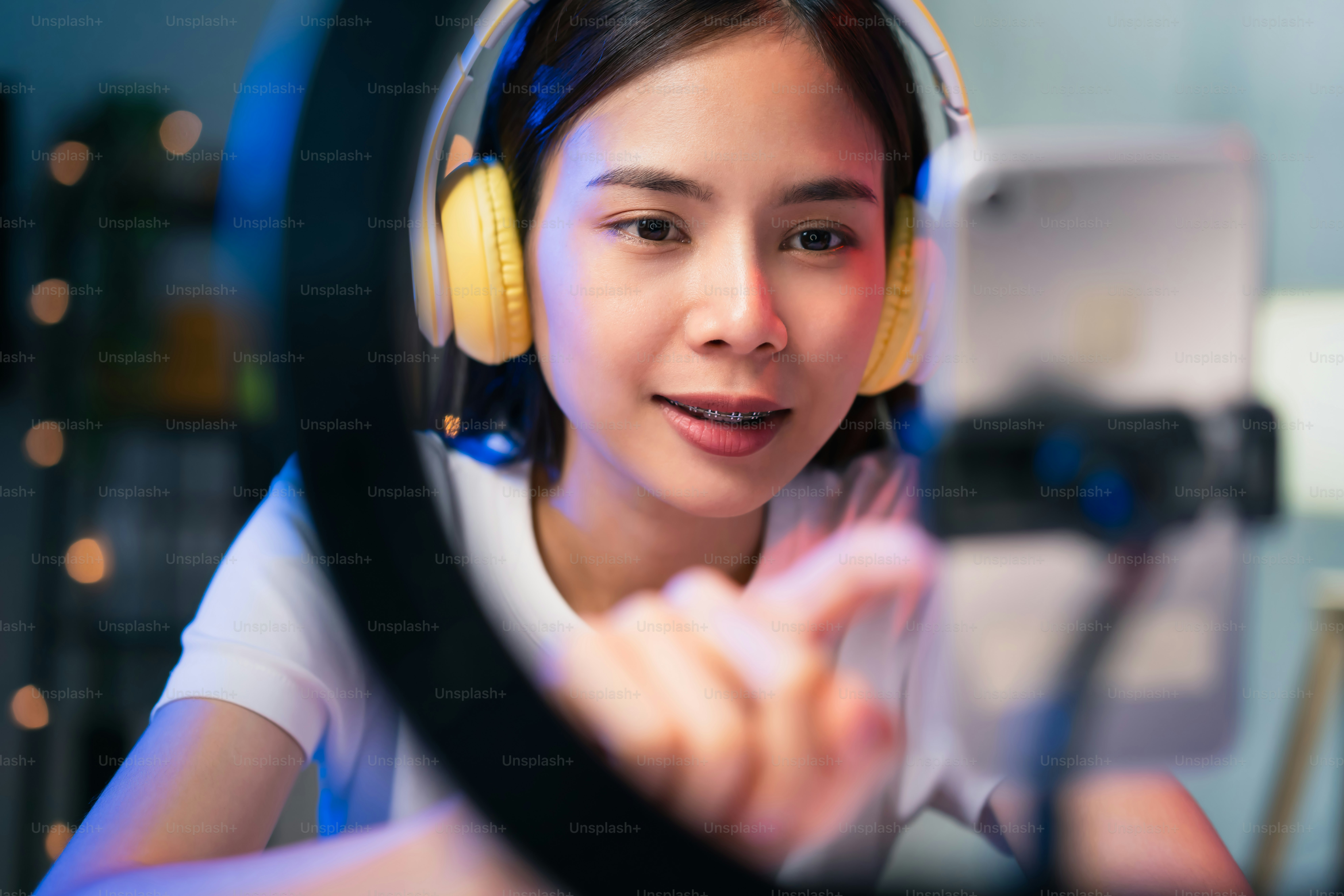 Smiling Young Asian woman wearing headset and live broadcasting on ...