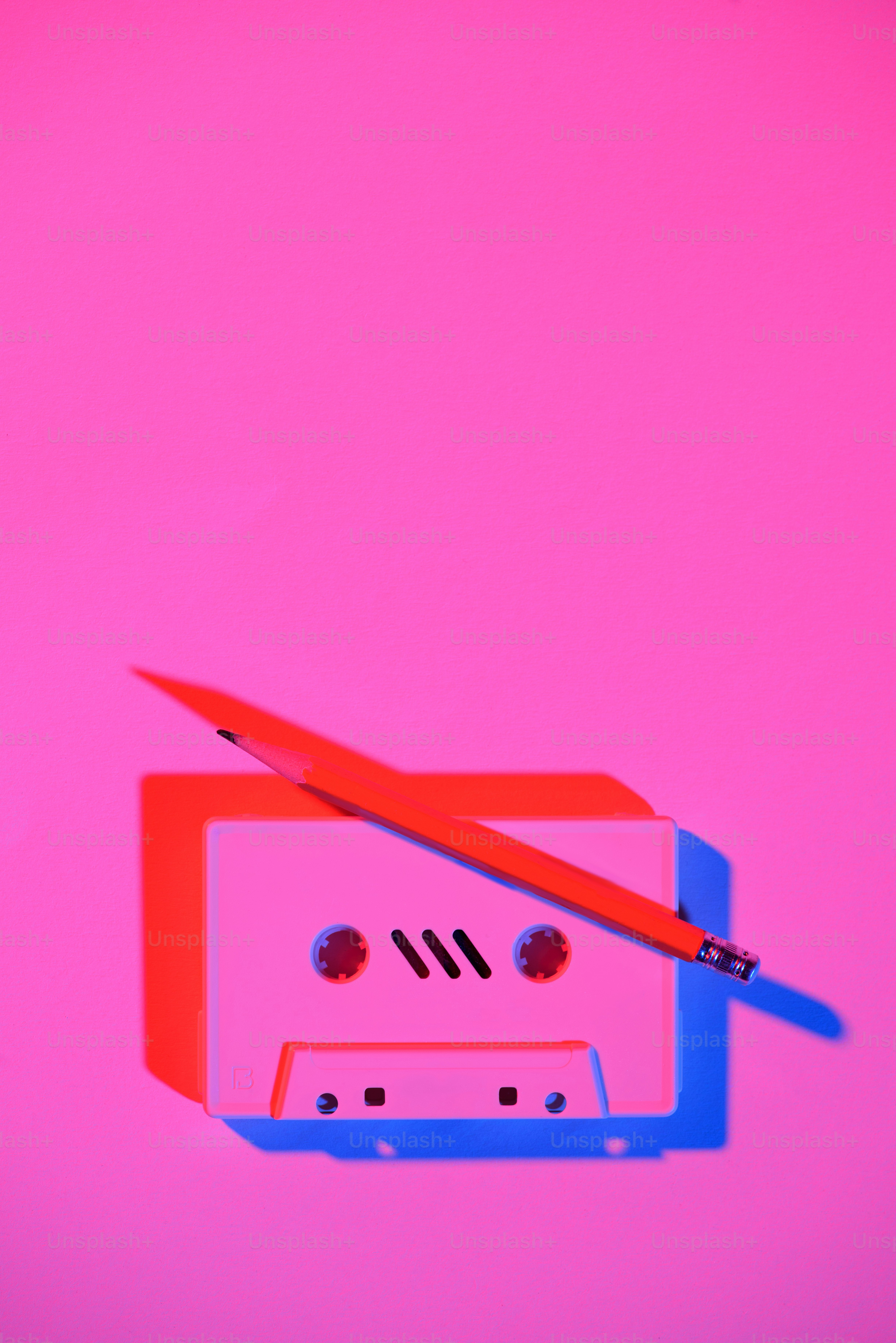 Close up view of retro audio cassette and pencils on pink backdrop ...
