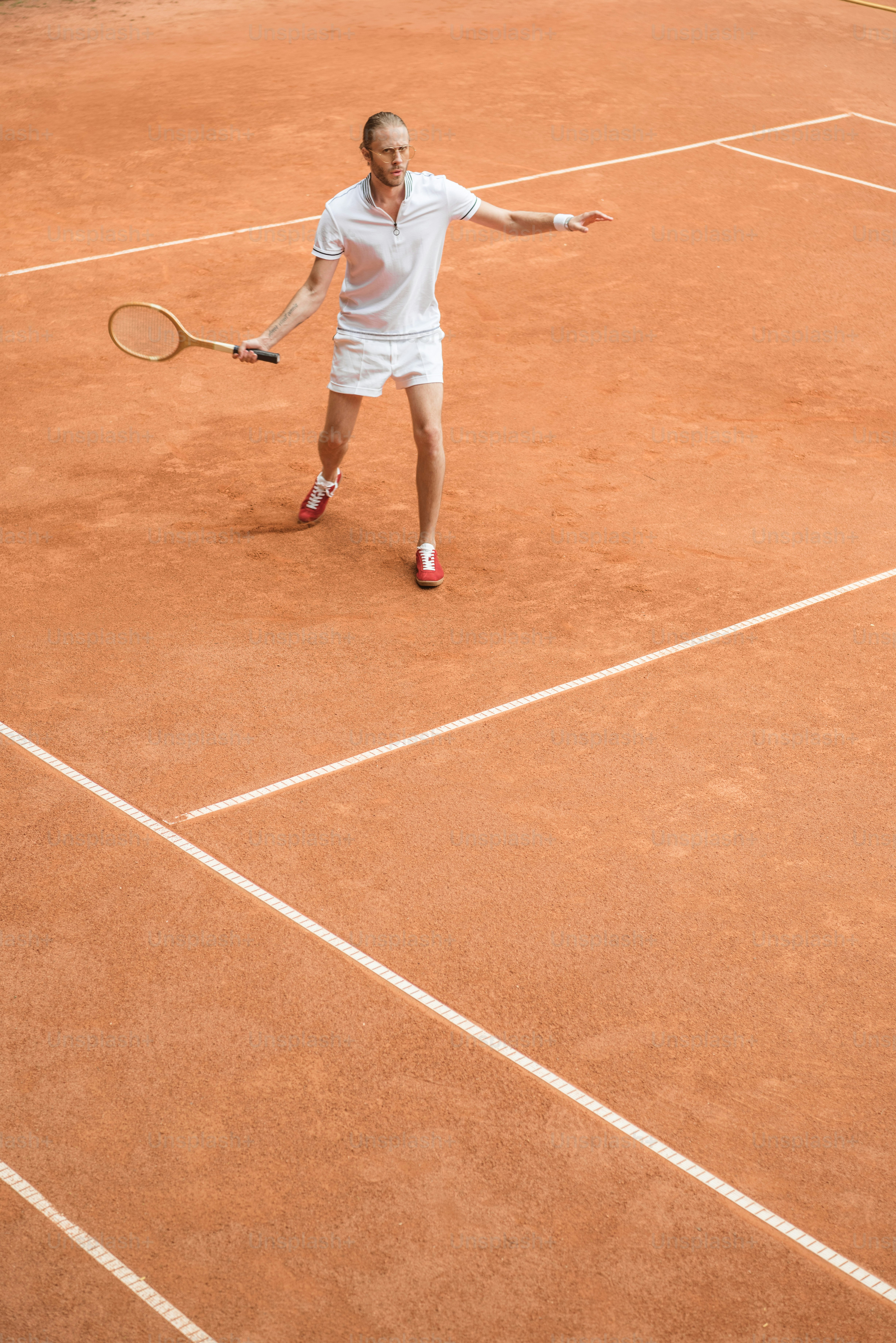 Old-fashioned tennis player training with retro wooden racket on brown ...
