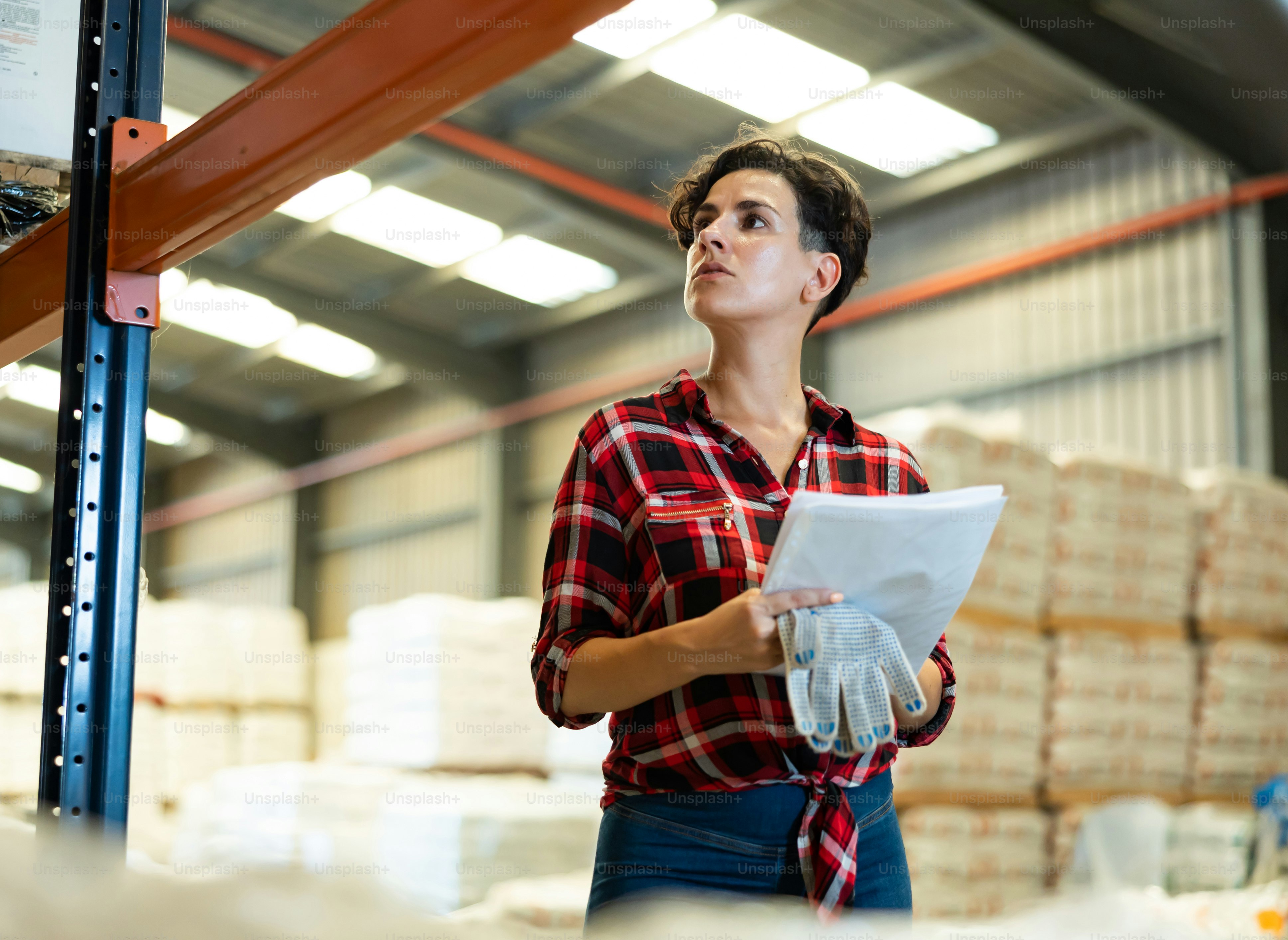 Female storekeeper checks the availability of goods with documents in ...