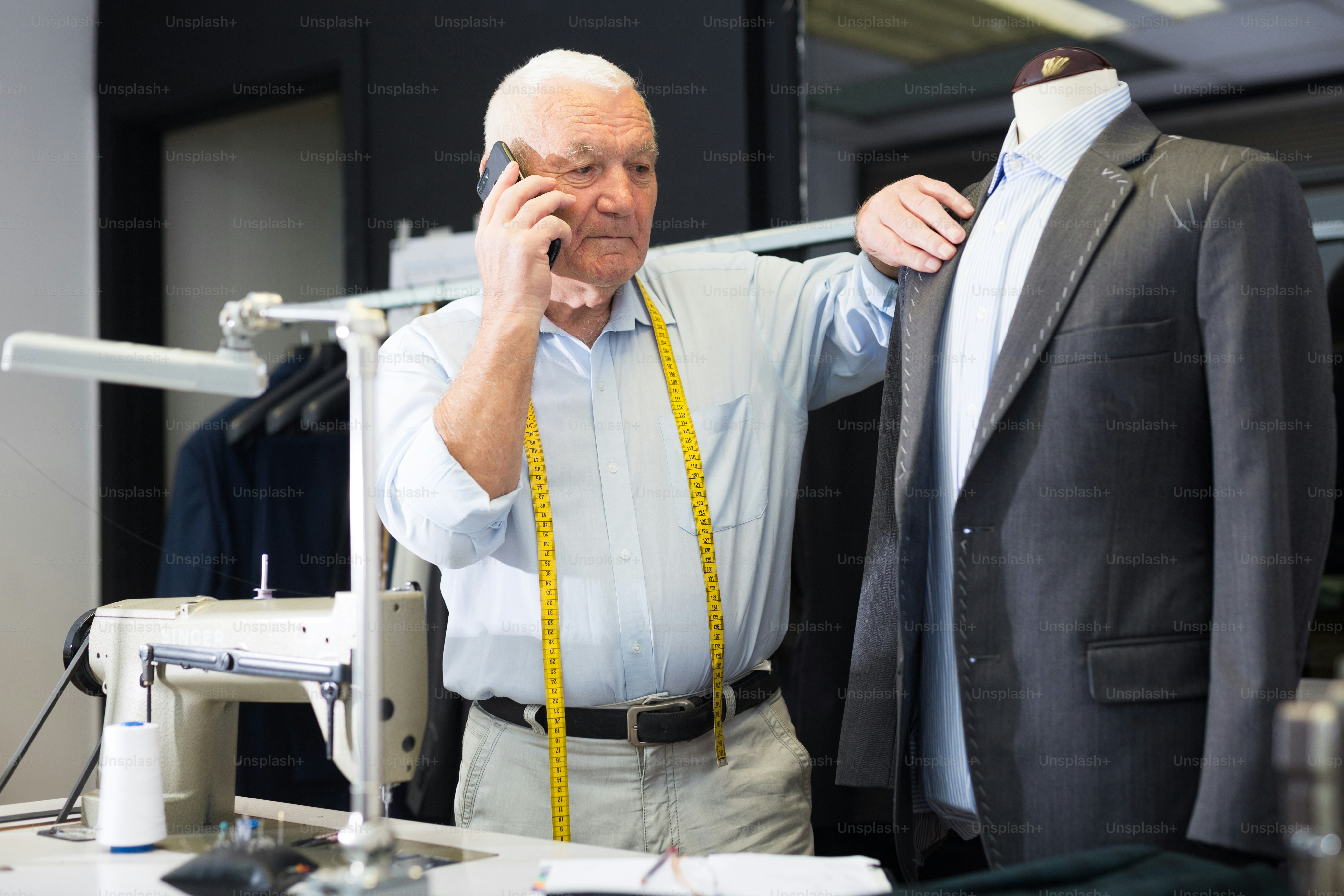 Professional tailor man talking on mobile phone and making notes in a ...