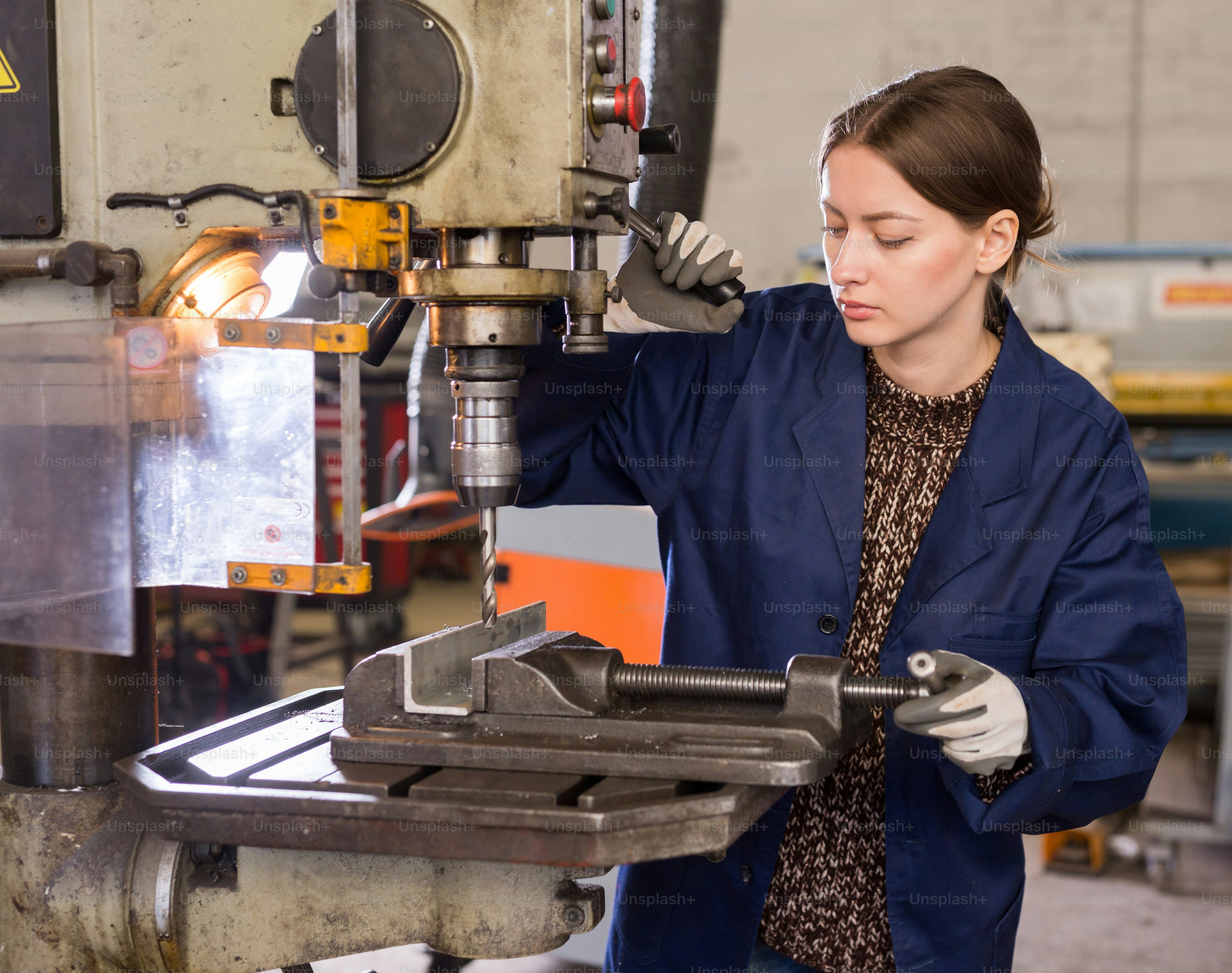 Portrait of confident woman mechanic using drilling machine in workshop ...