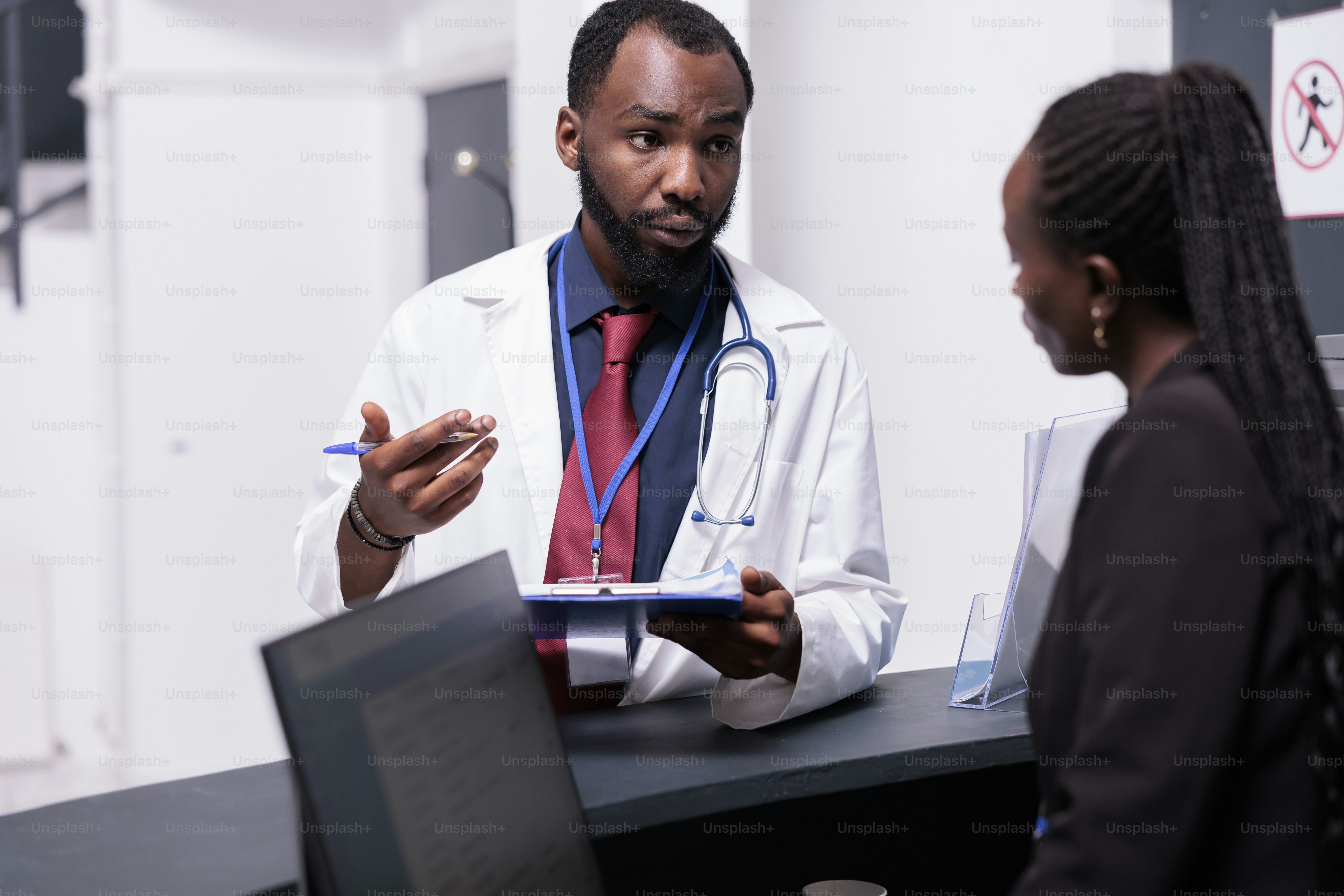 General practitioner talking to receptionist about healthcare insurance ...