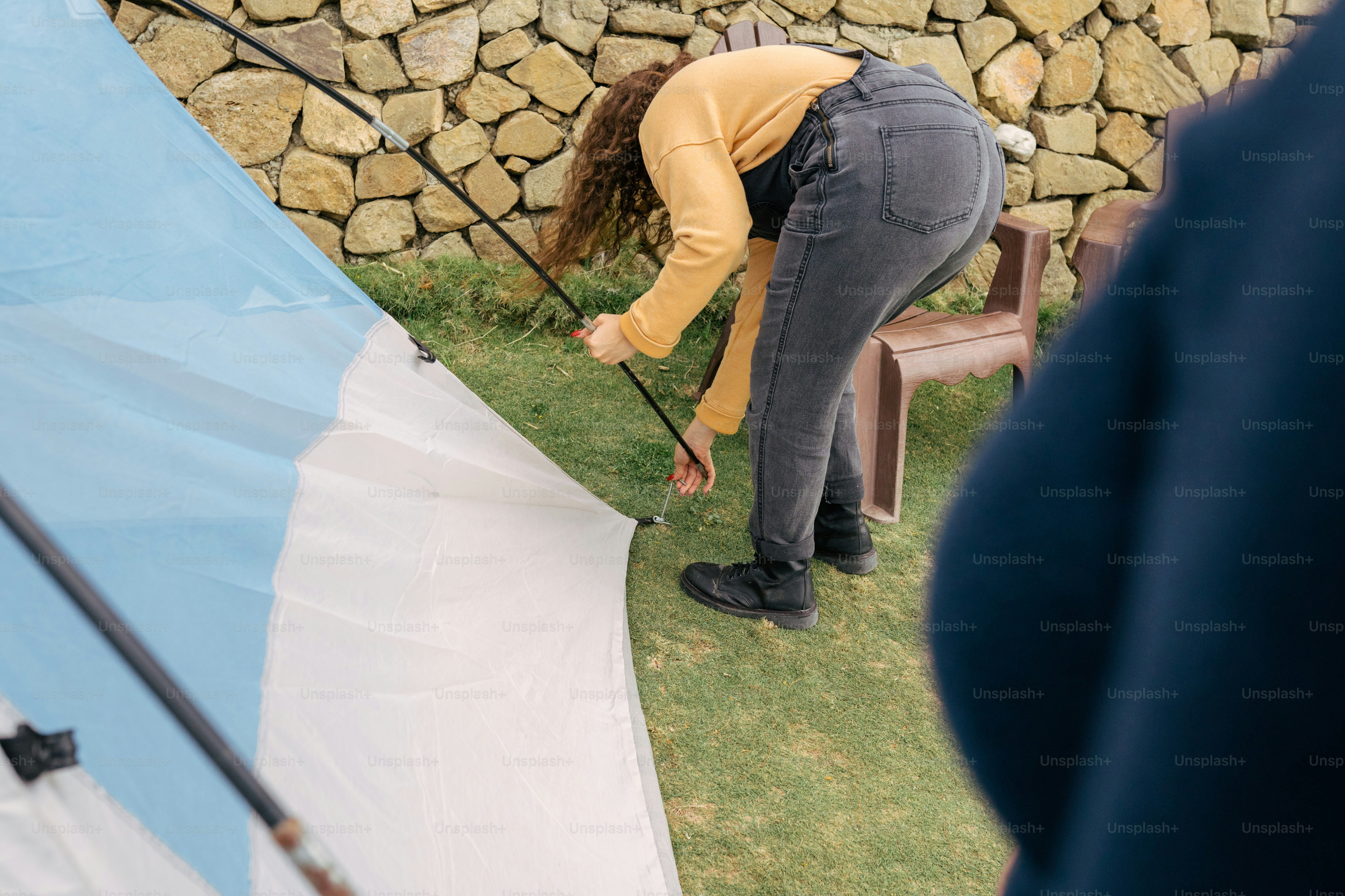 A woman bending over a blue and white umbrella photo – Tent Image on ...
