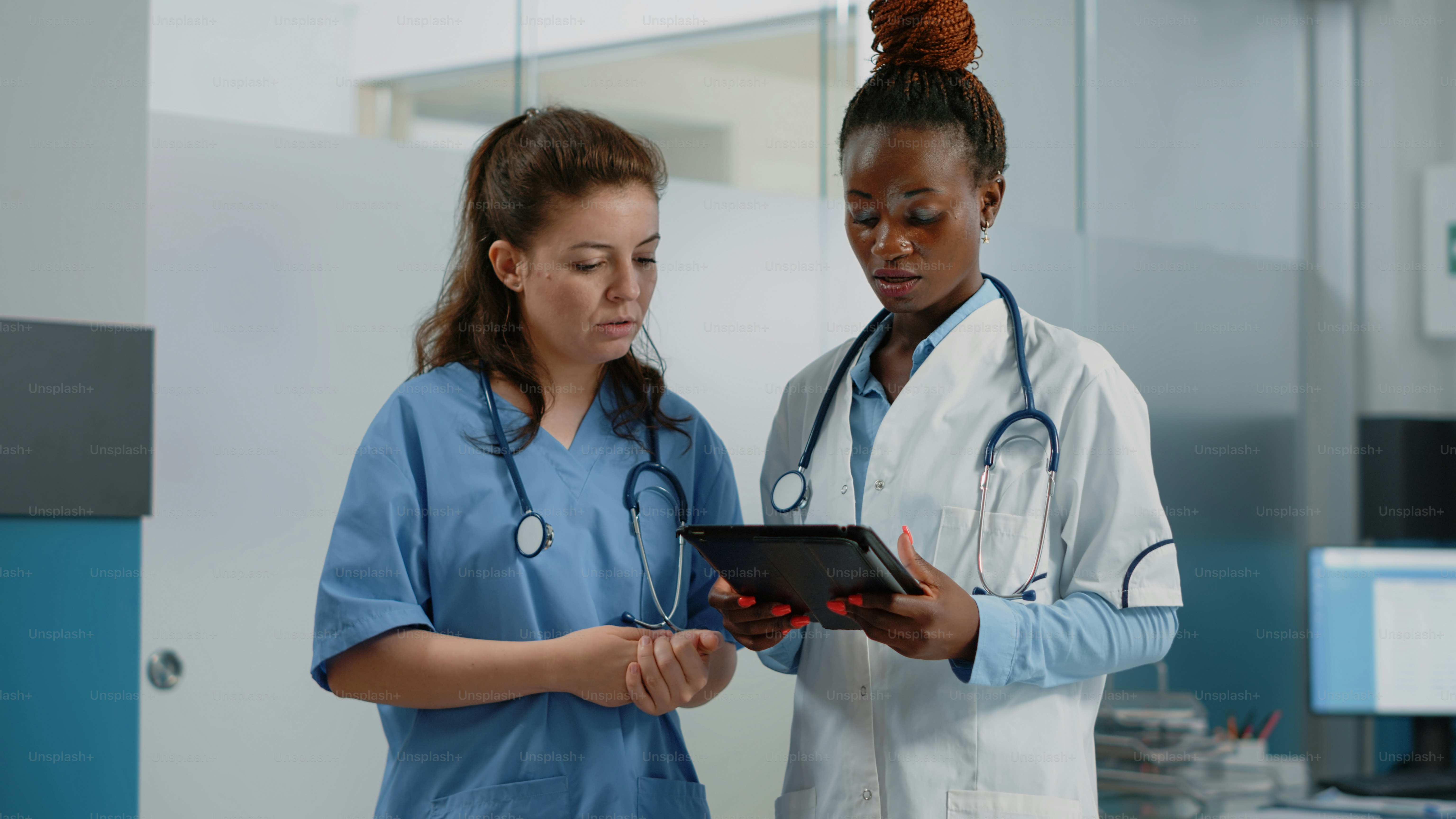 Group of doctor and nurse analyzing diagnosis on tablet in cabinet. Medical team using ...