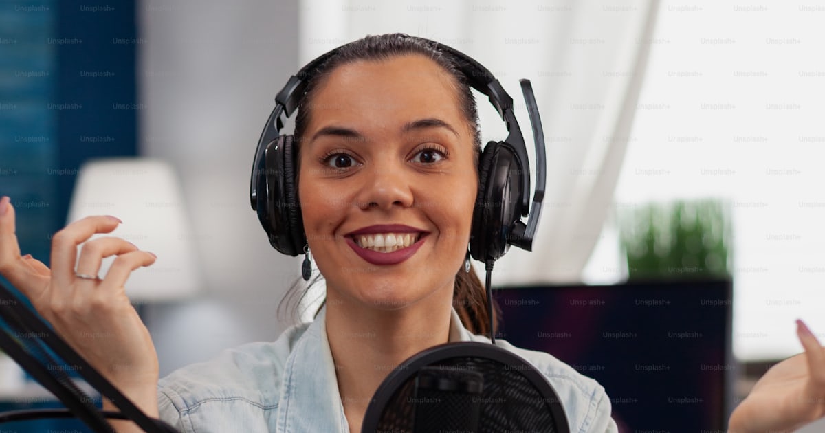 マイクを使った笑顔のプレゼンターストリーミングポッドキャストのポートレート。カメラにライブストリームを記録するヘッドフォンを持つソーシャル