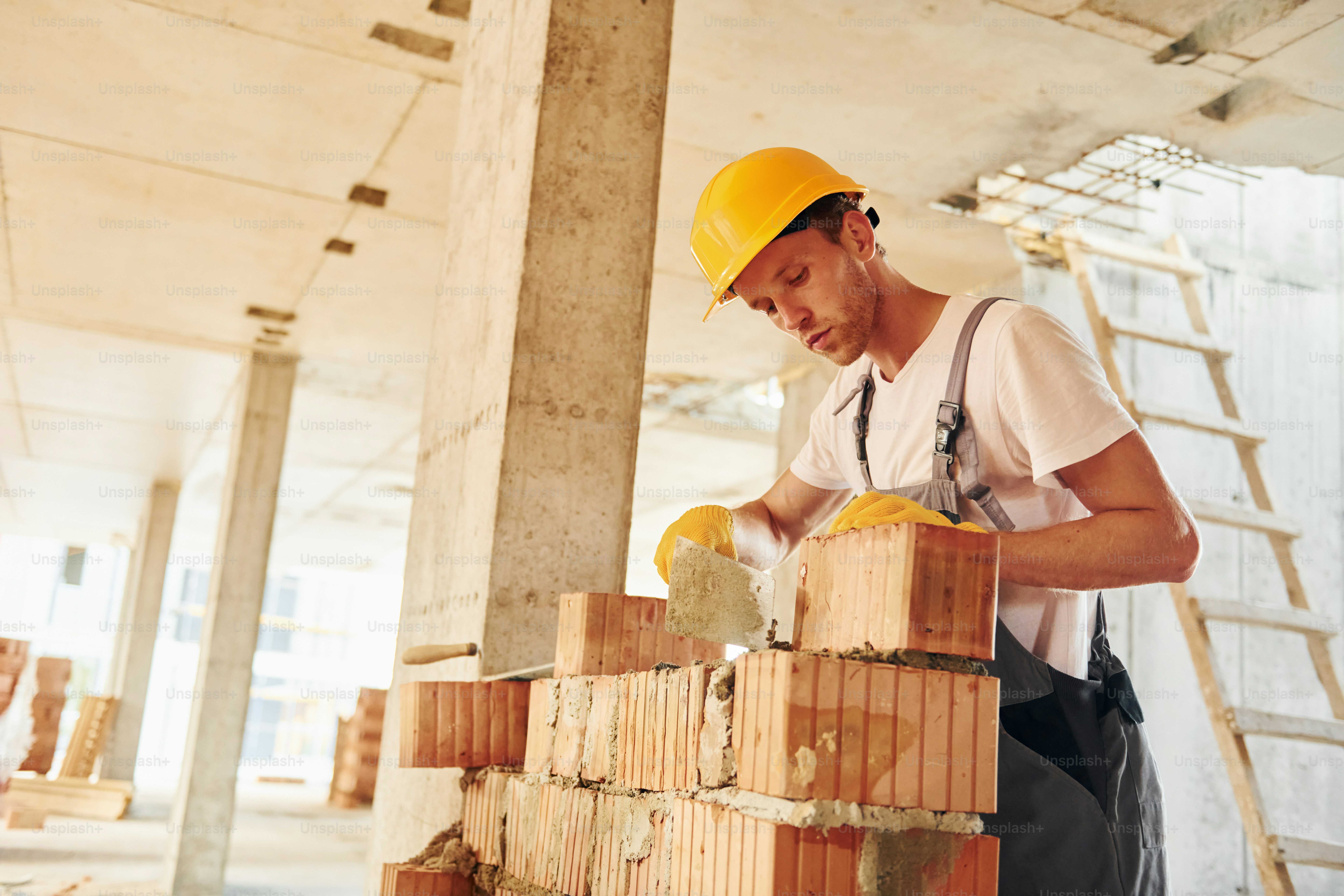 Sitting outdoors. Young man working in uniform at construction at ...