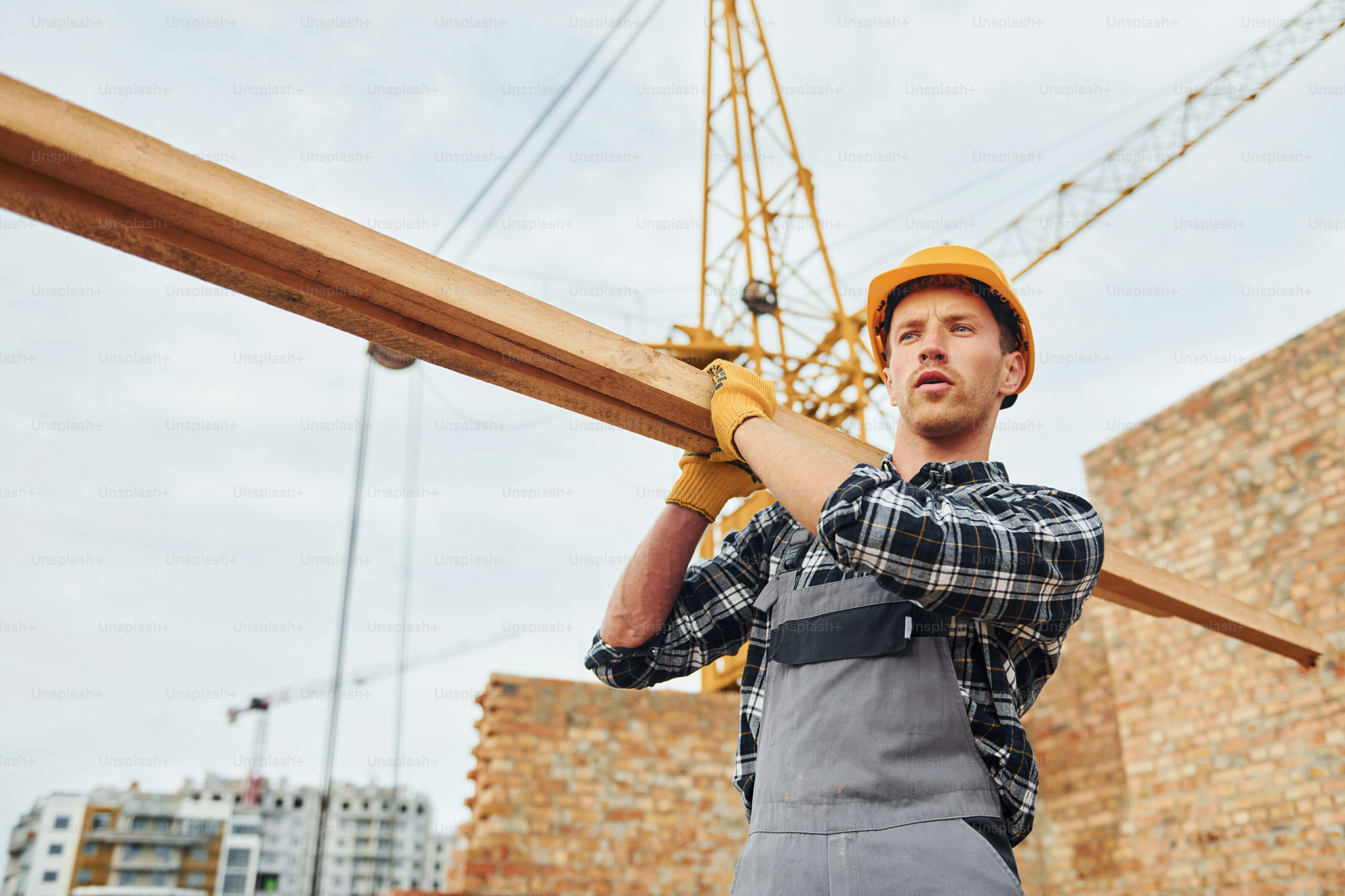 Transporting wooden boards. Construction worker in uniform and safety ...