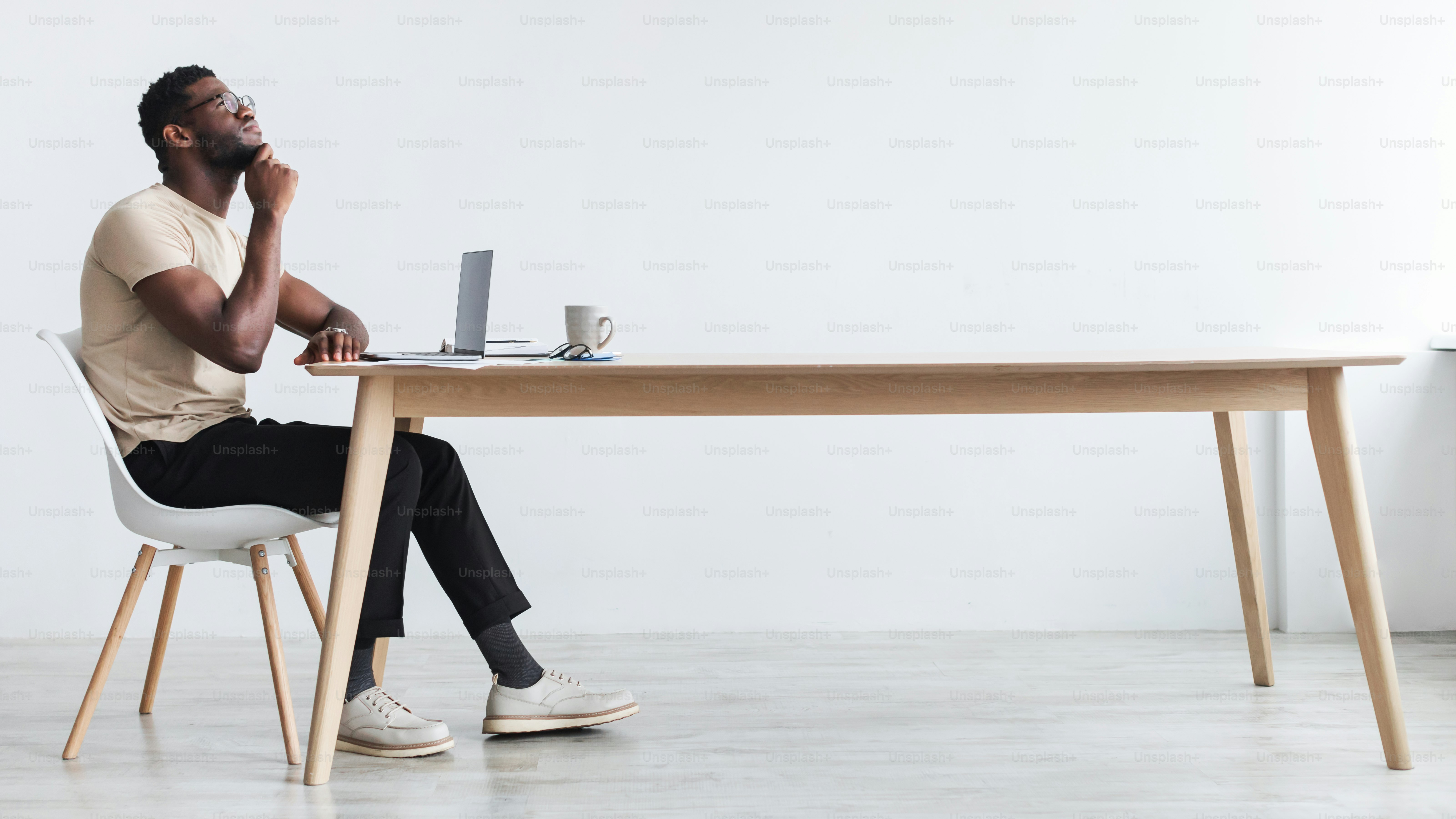 Side view of pensive young black guy using laptop, sitting at desk ...