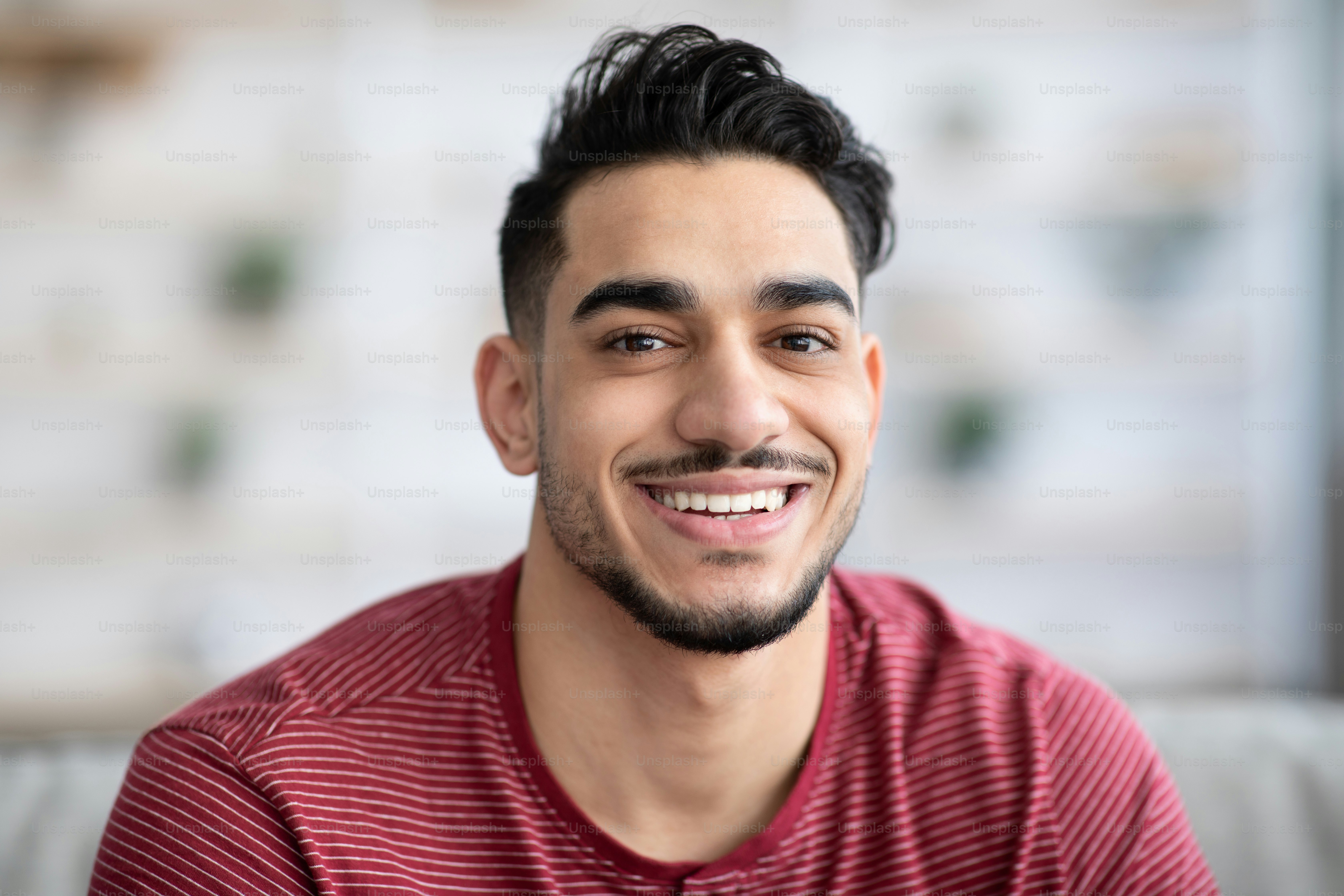 Portrait en gros plan d’un beau mec arabe souriant à la caméra tout en ...