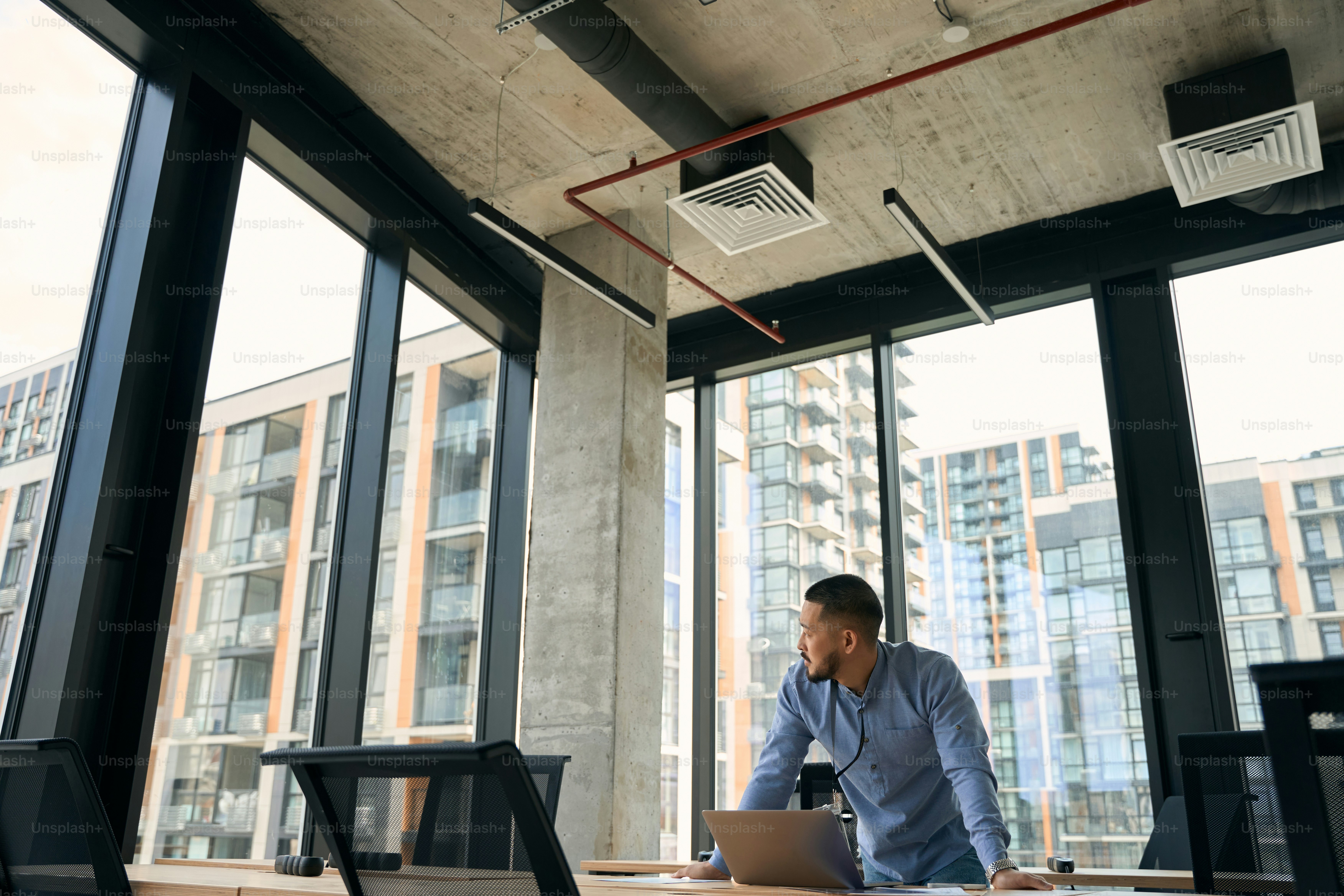 Corporate manager leaning on office desk with his portable computer and ...