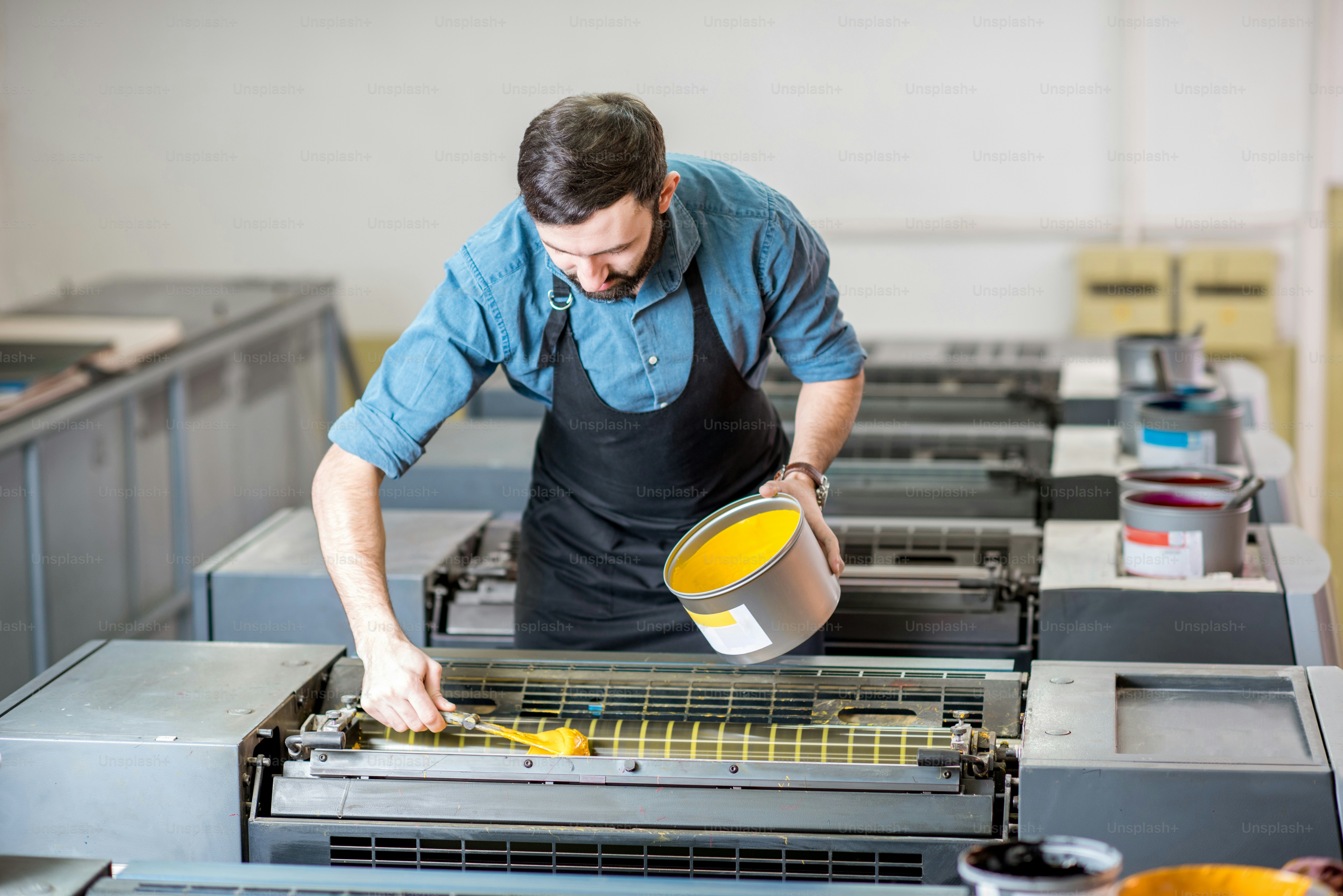 Typographer filling yellow paint into the offset machine at the ...