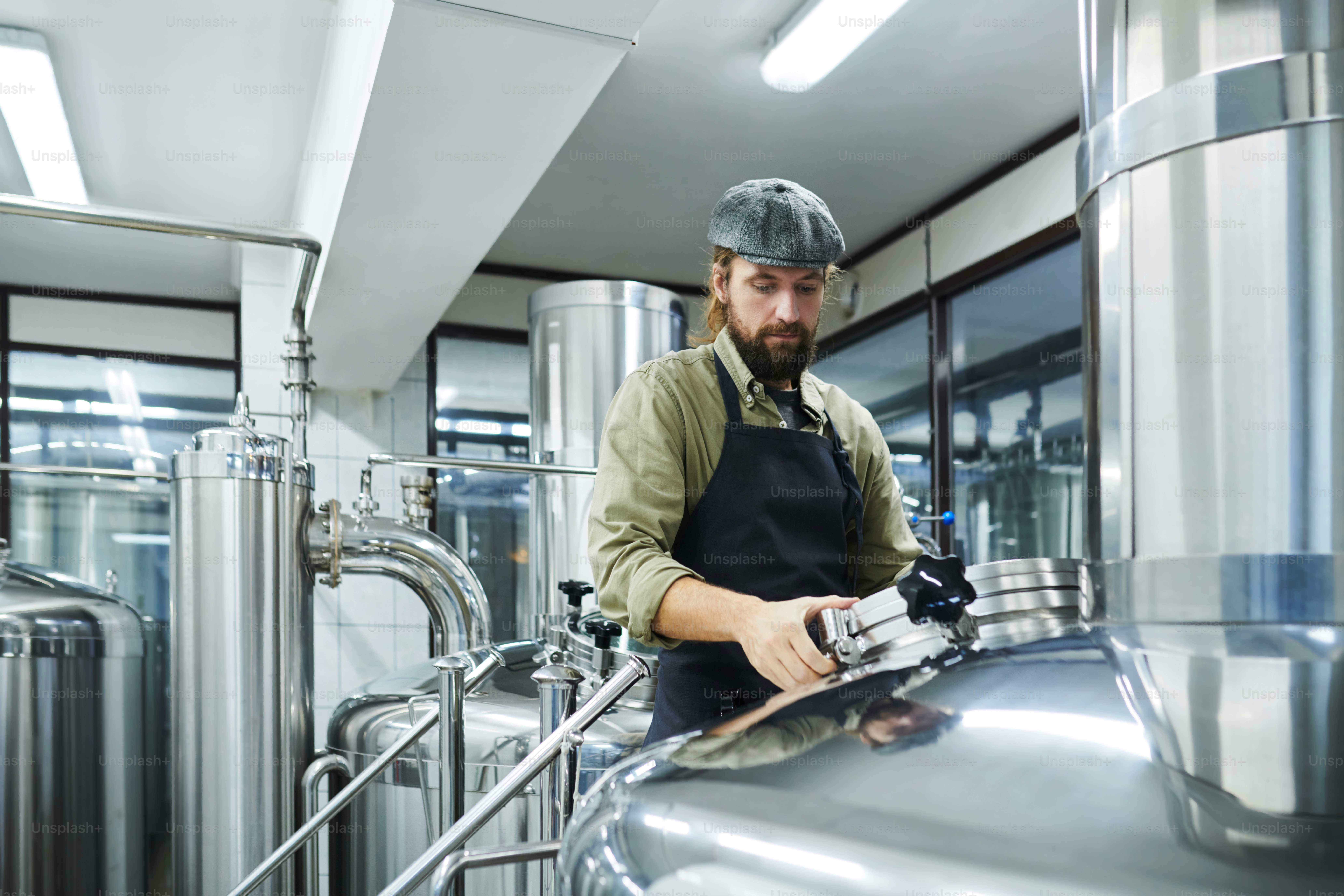 Small brewery worker checking tanks with fermenting beer photo ...
