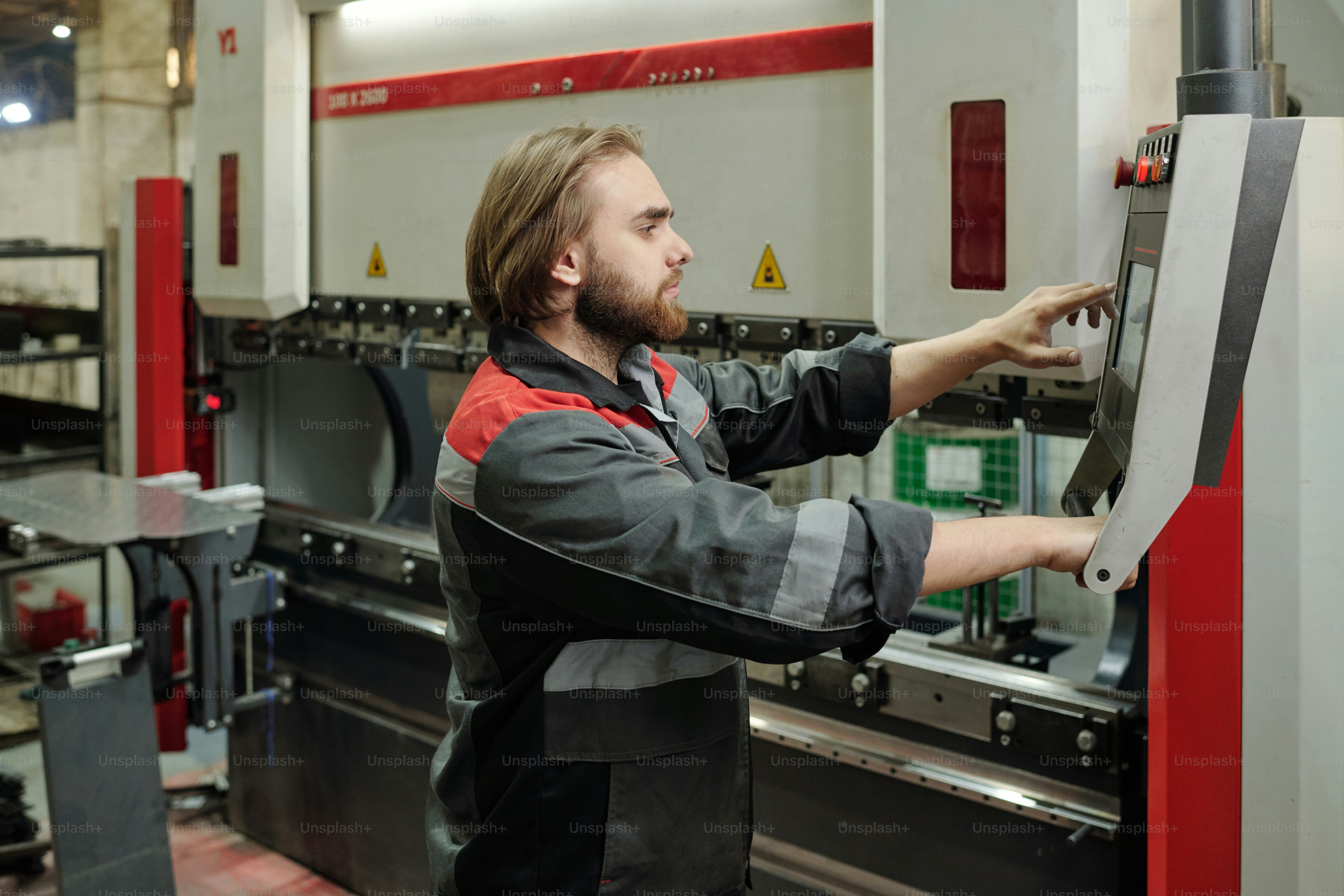 Young male technician in workwear standing in front of control terminal ...