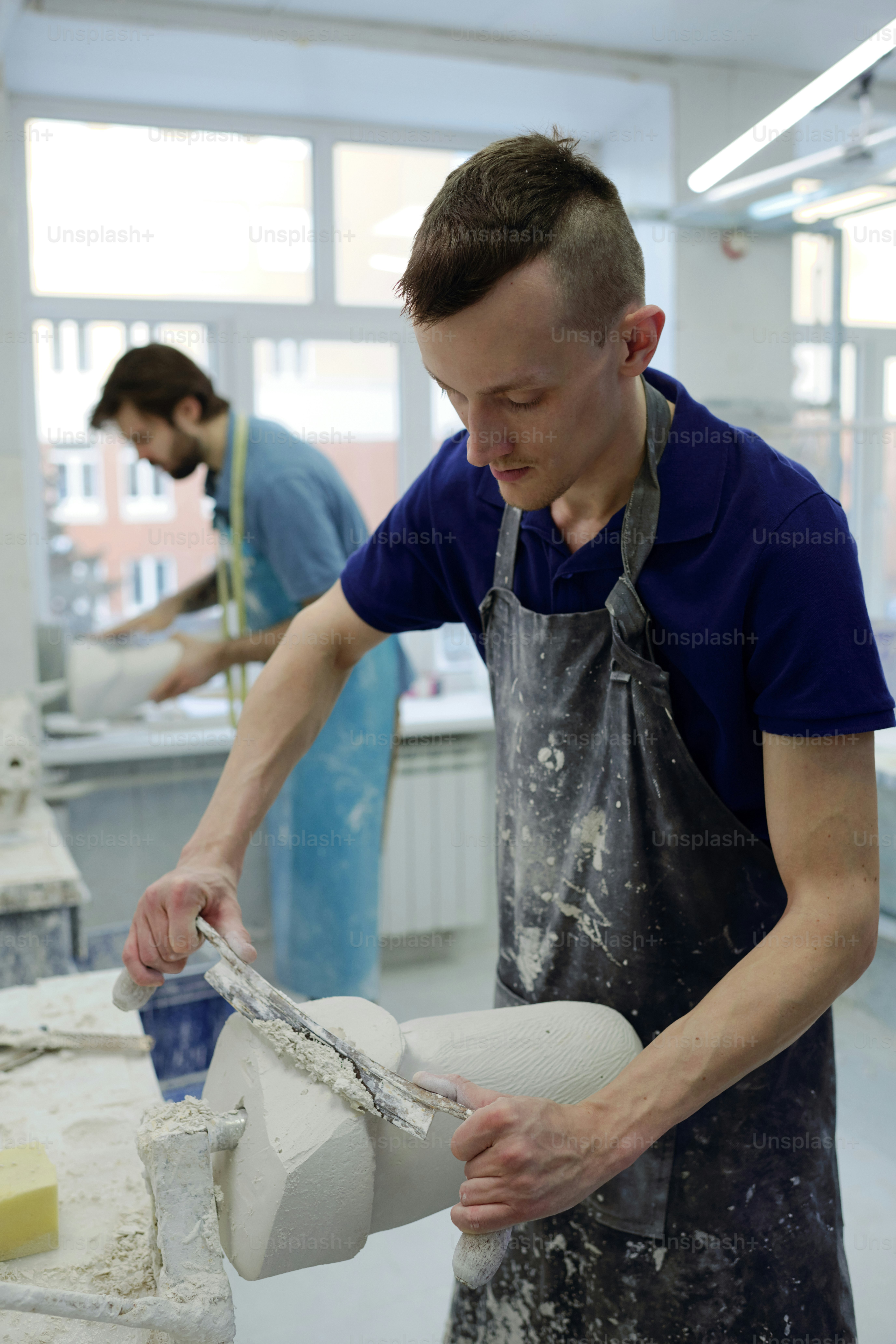 Worker of prosthetic factory cutting upper part of plaster cast while ...