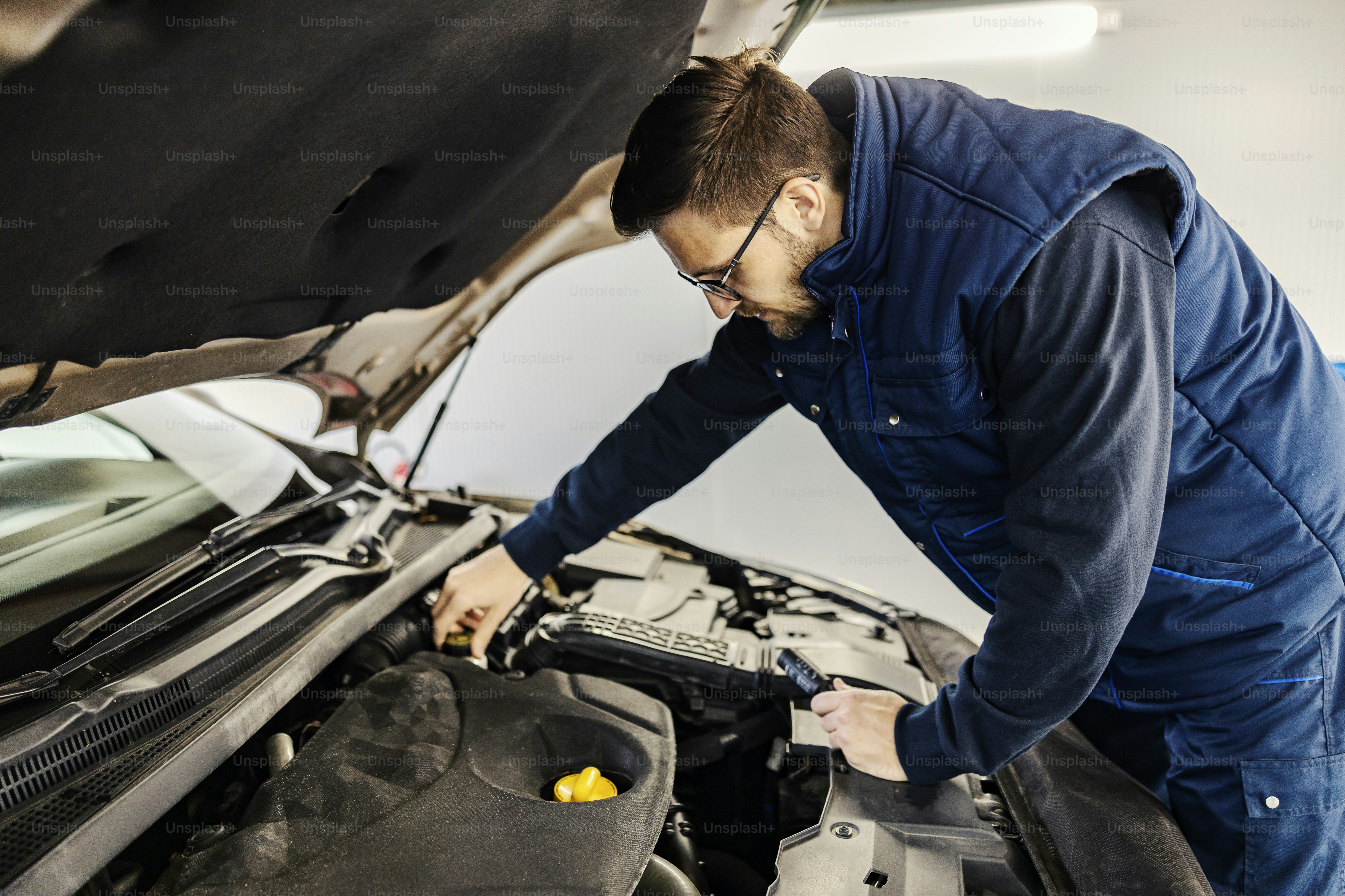 Un mécanicien automobile répare un moteur de voiture dans un garage ...