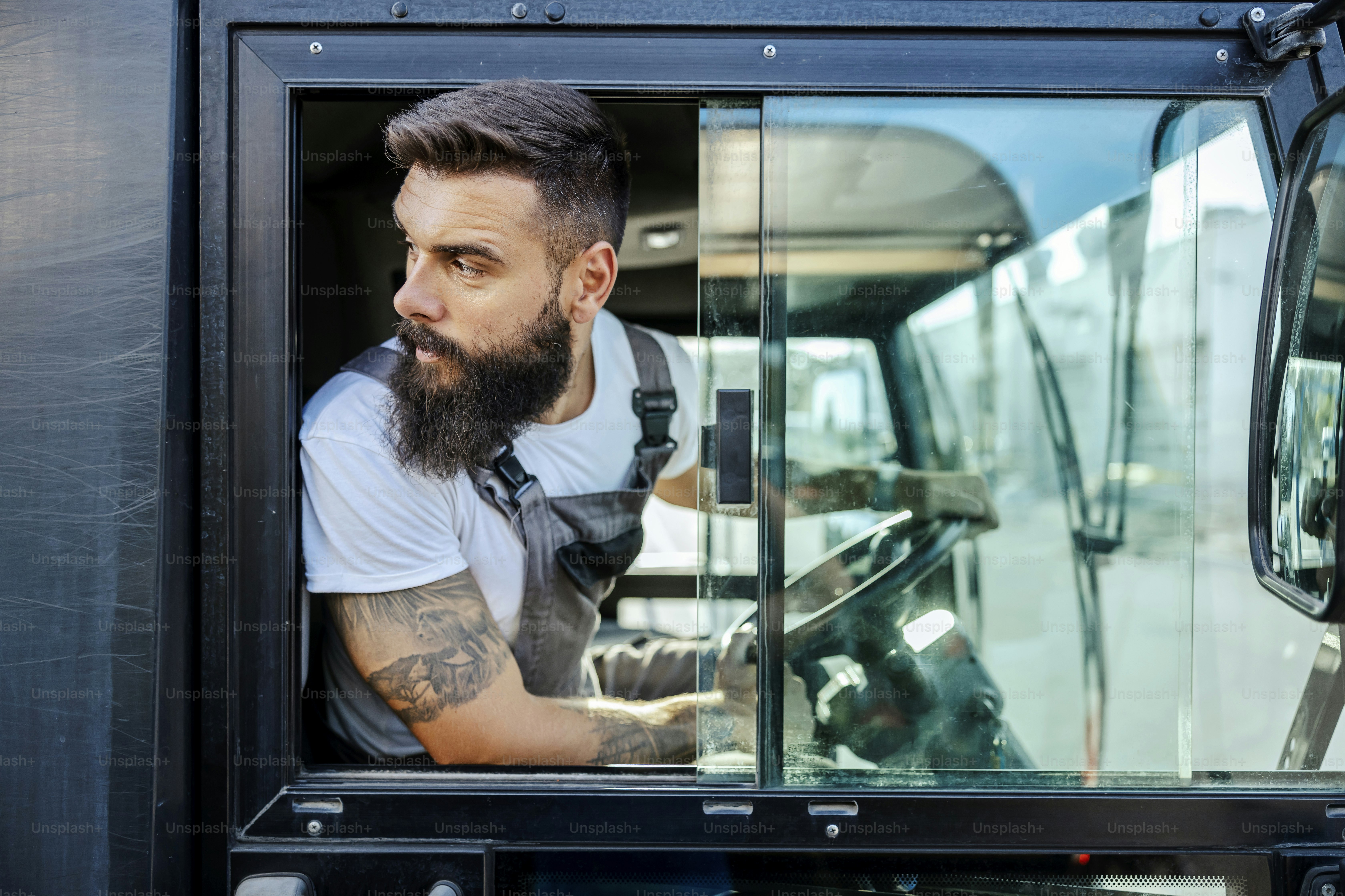Un conductor cuidadoso en mono sentado en un vehículo y estacionándolo ...