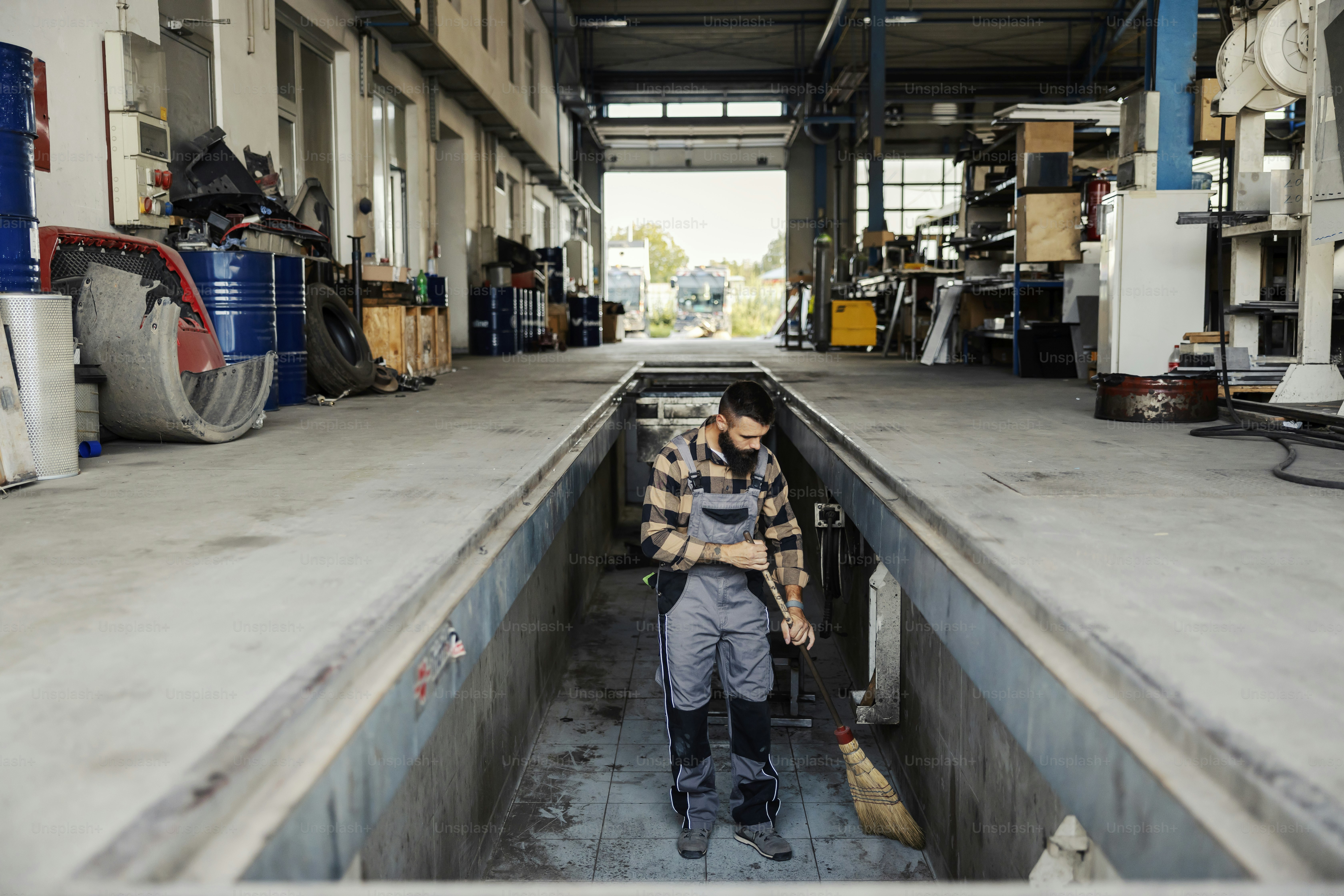 A mechanic's workshop worker sweeping dust in mechanic's pit. photo ...