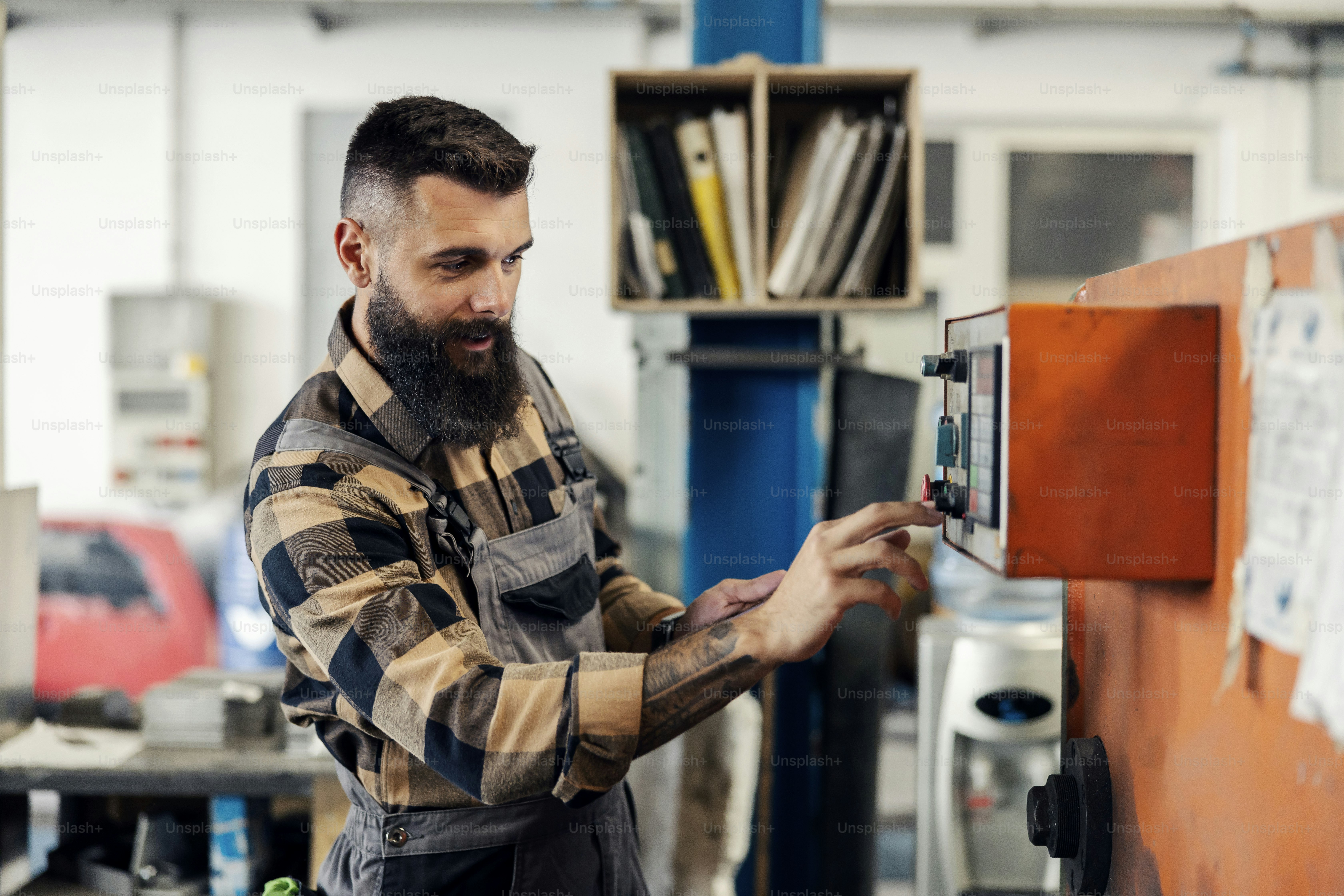 An industry worker pressing control button on machine. photo – Beard ...