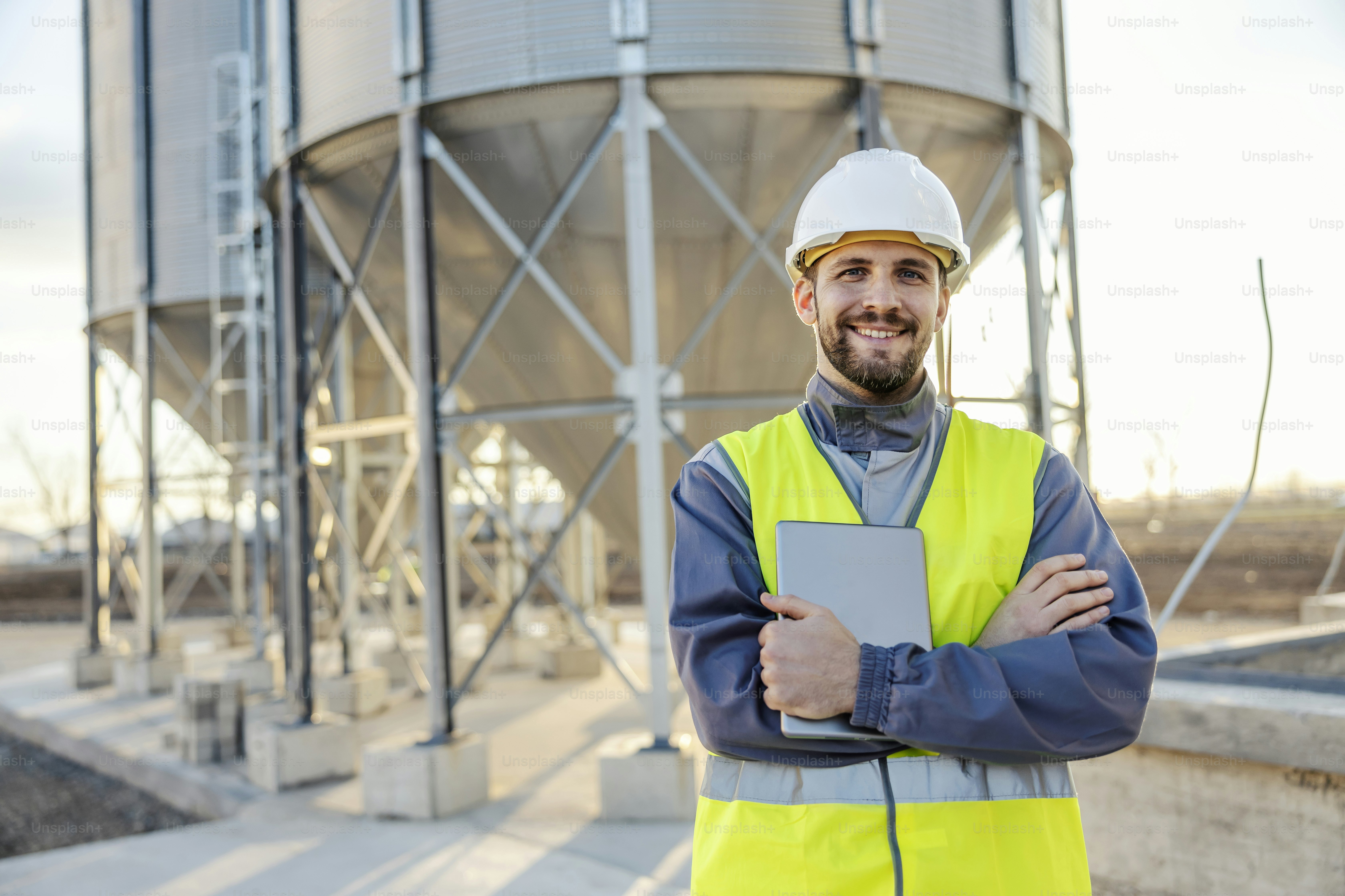 A manager is standing in front of the silos full of supplies and ...