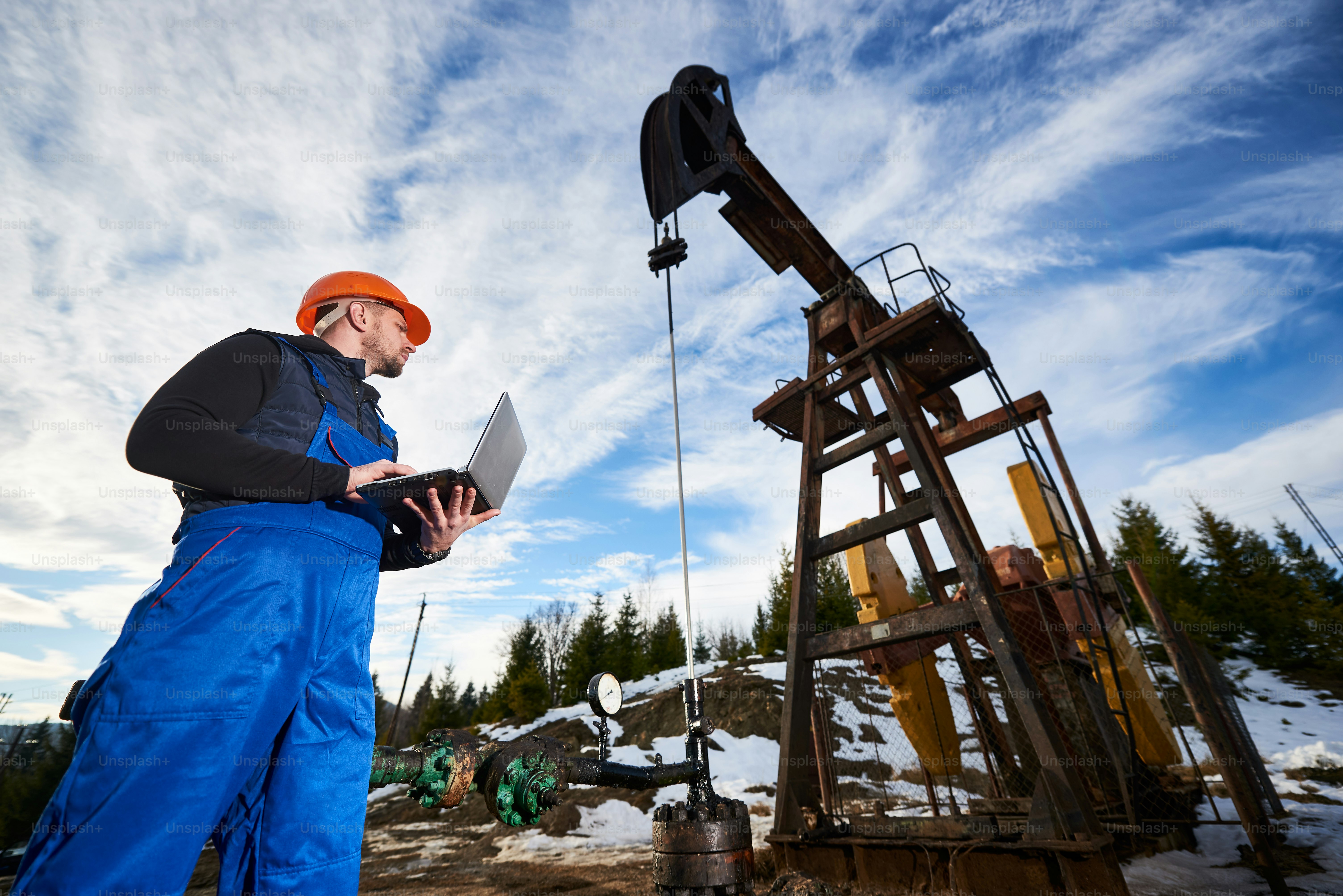 Oil man holding notebook and looking at oil pump rocker-machine. Male ...