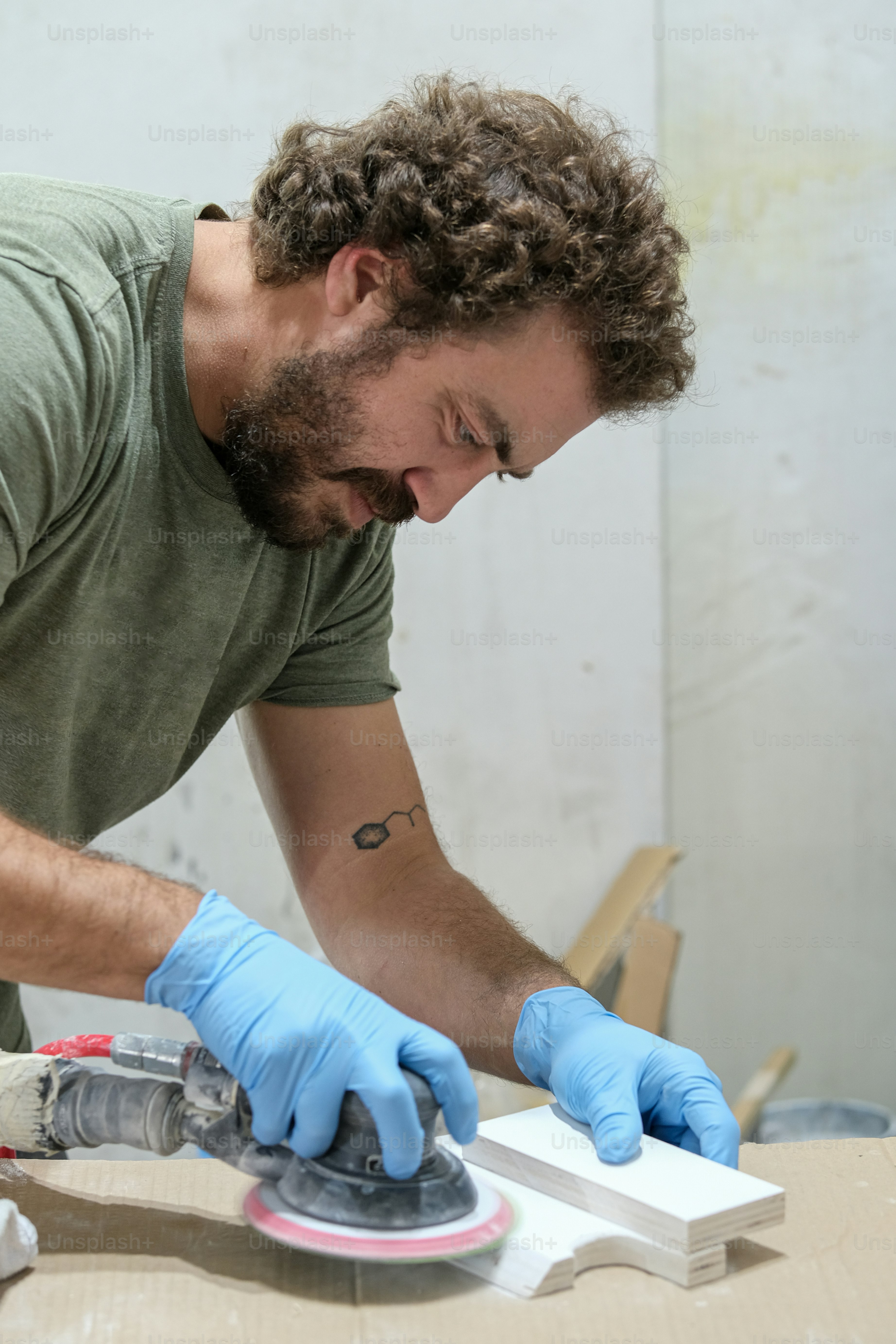 A man sanding a piece of wood with a sander photo – Construction Image ...