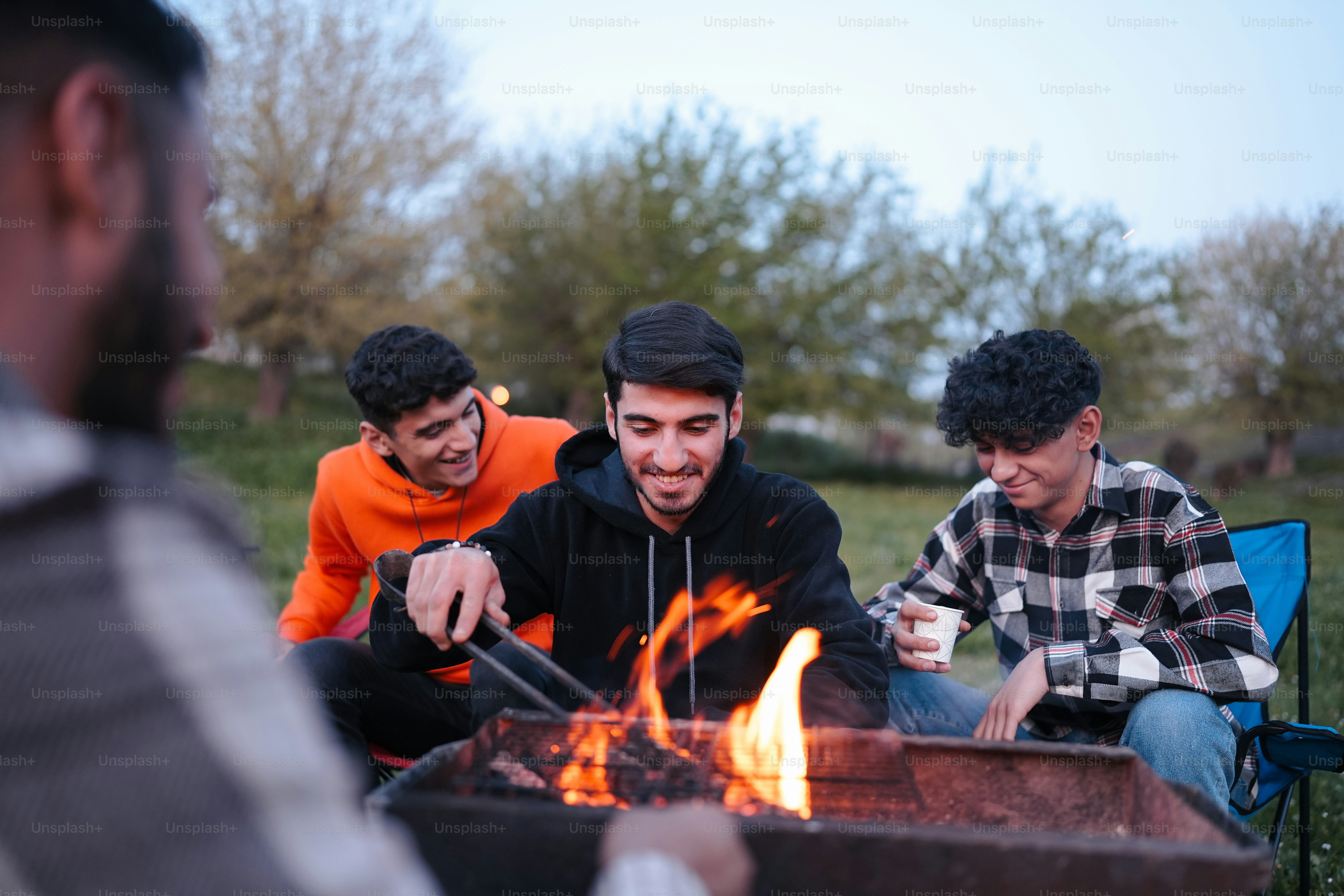 A group of people sitting around a fire pit photo – Charcoal Image on ...