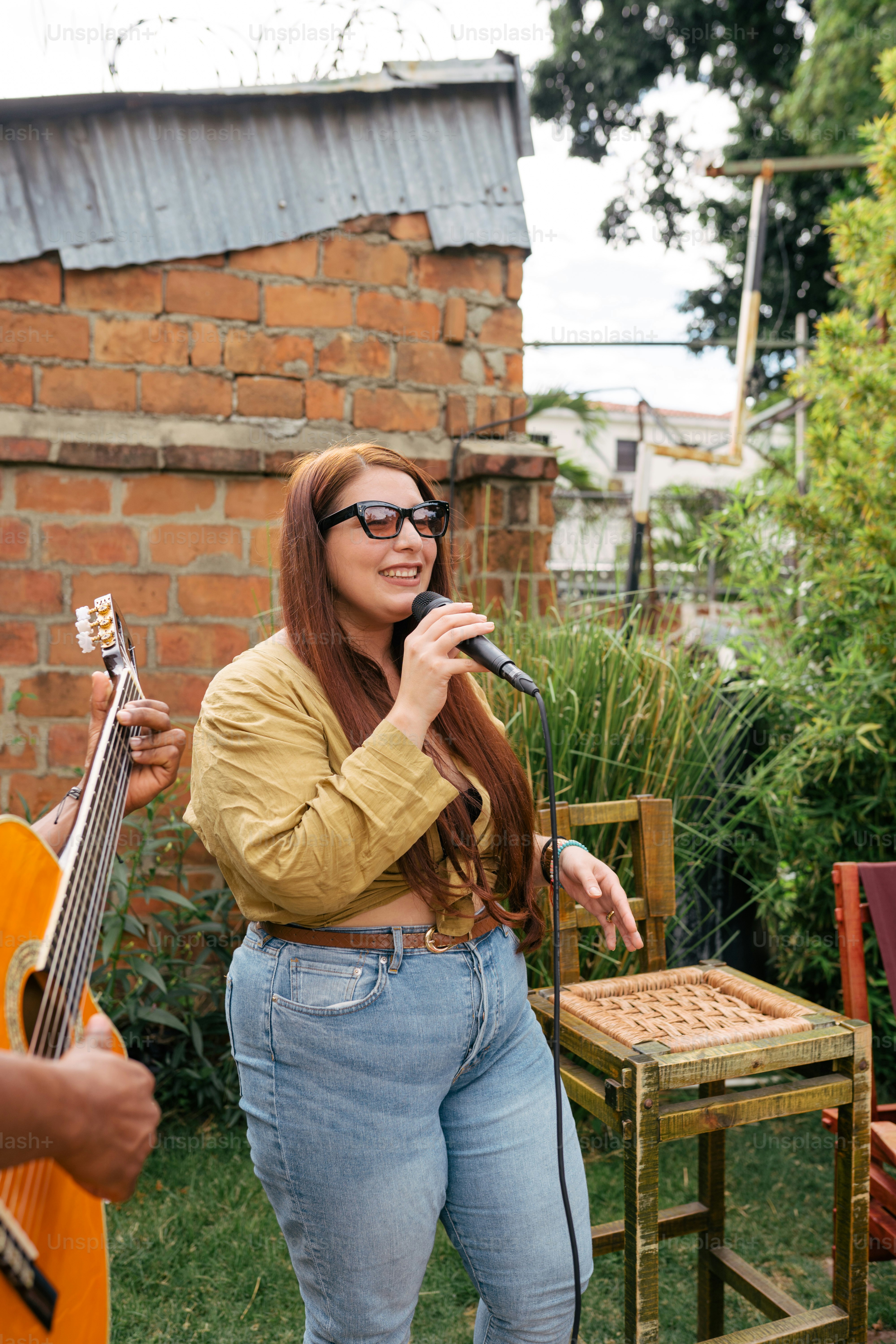A woman with glasses is singing into a microphone photo – Singer Image ...