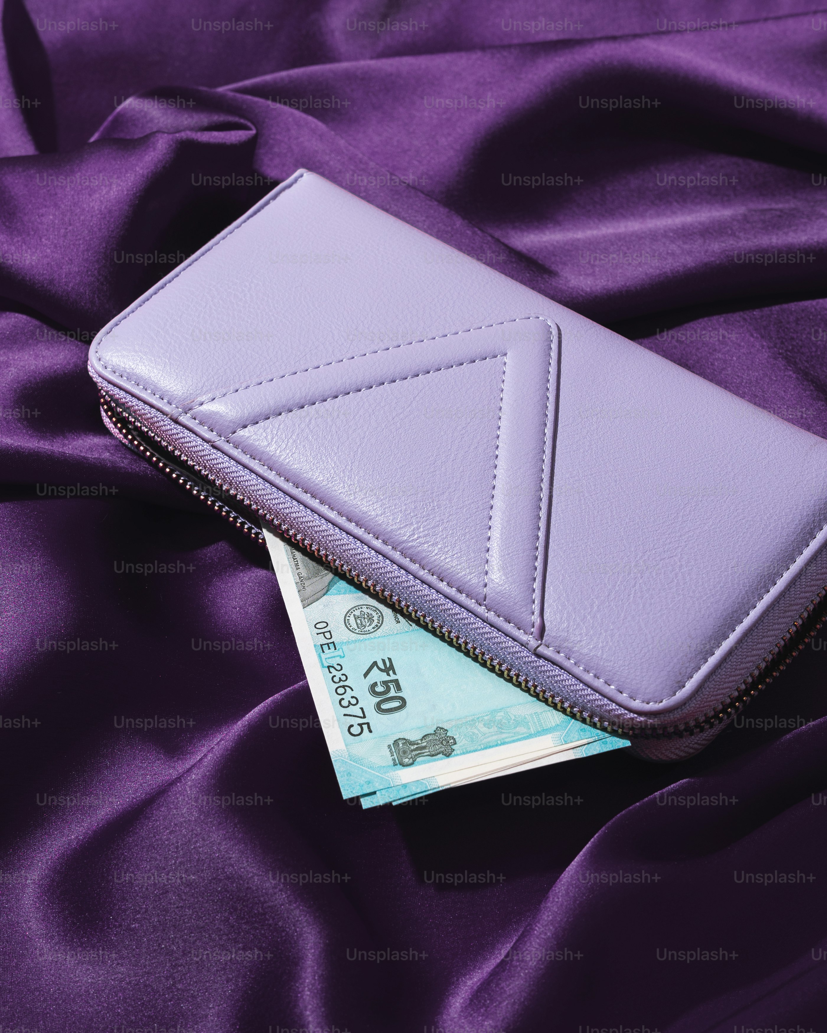 A purple wallet sitting on top of a purple cloth photo – Purse Image on ...