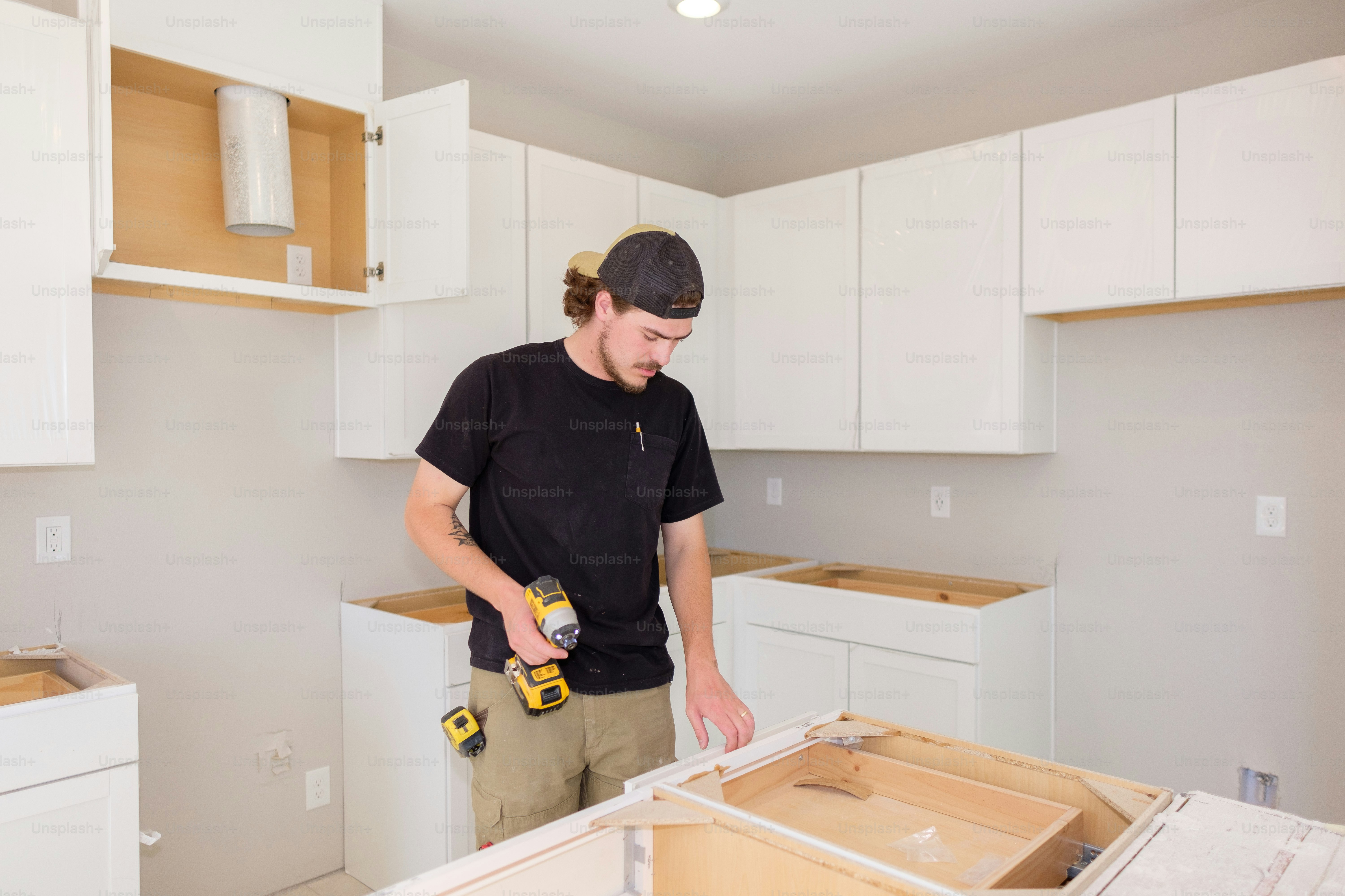 A man in a black shirt and some white cabinets photo – Building Image ...