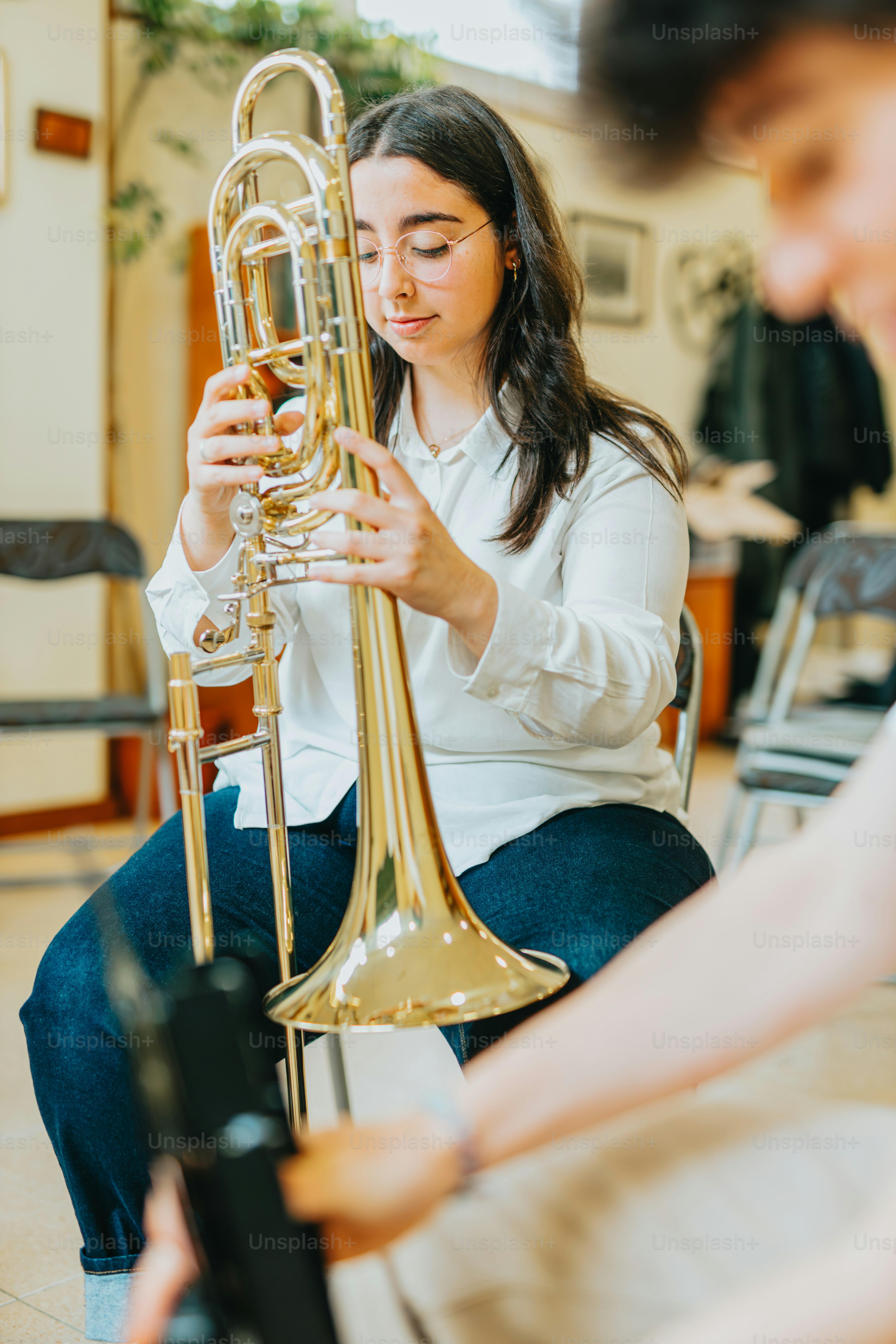 A woman sitting on a chair playing a trumpet photo – Musician Image on ...