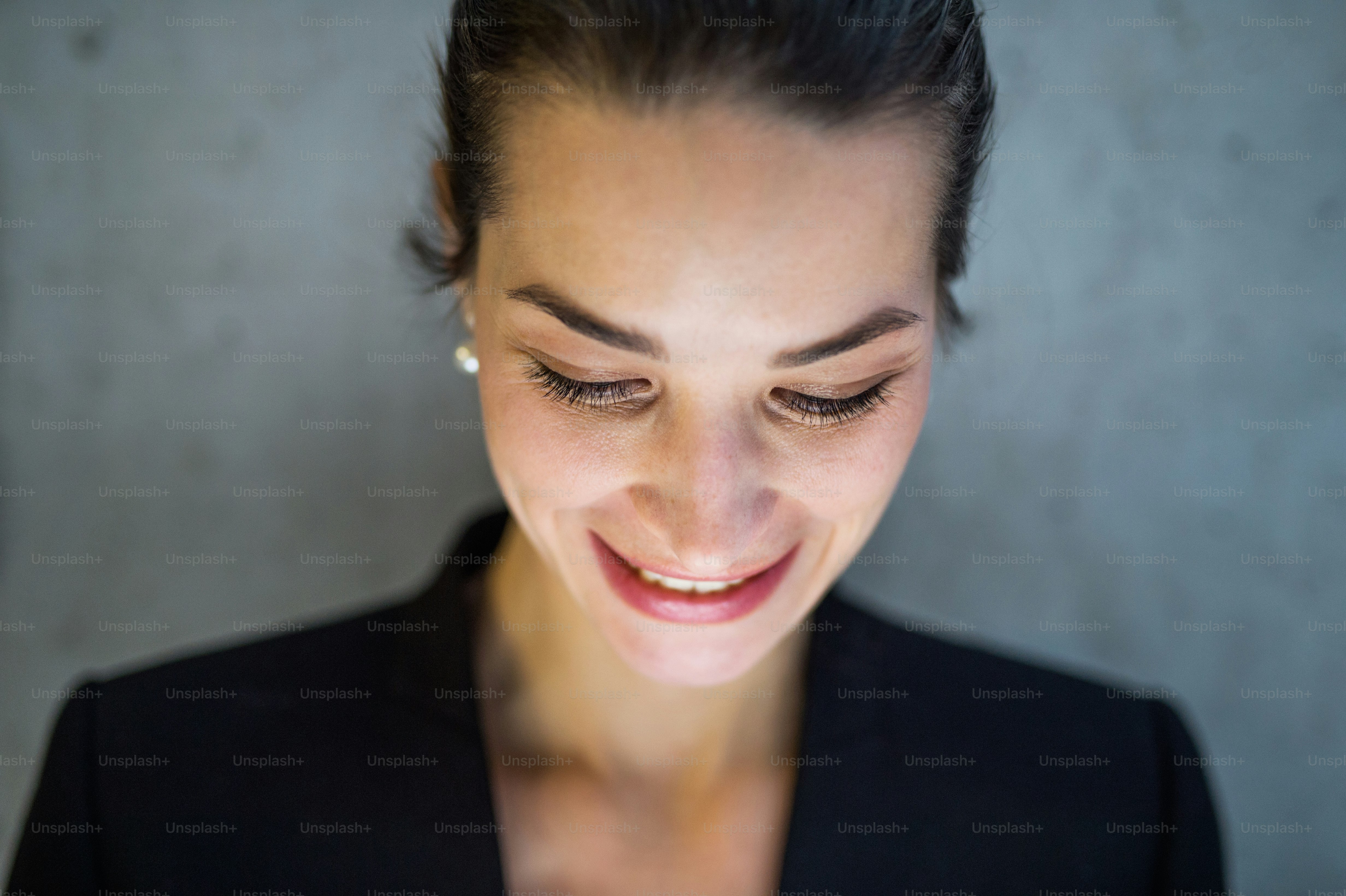 A close-up portrait of young businesswoman standing in office, looking ...