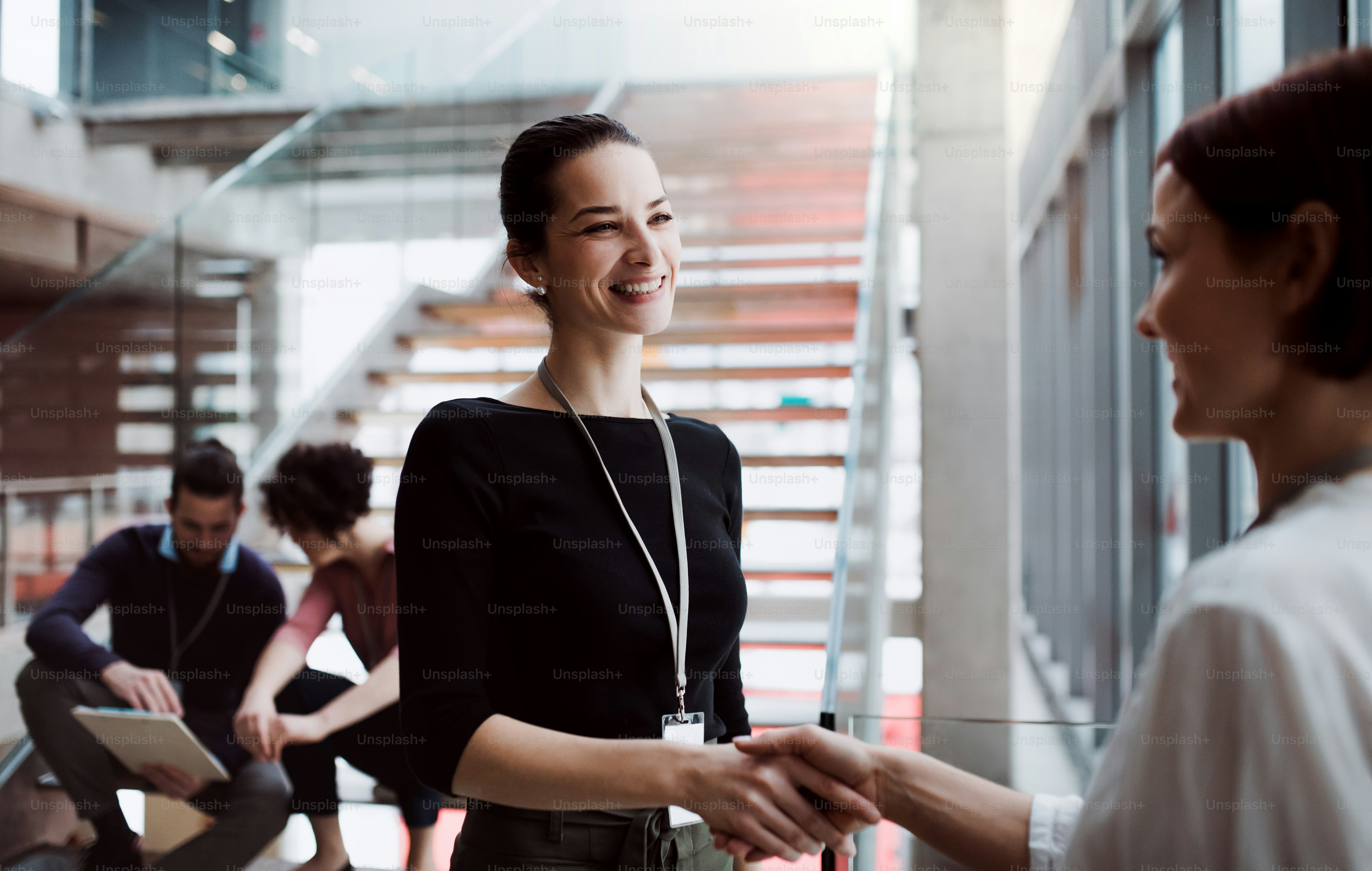 A group of young businesspeople standing on a staircase, shaking hands ...